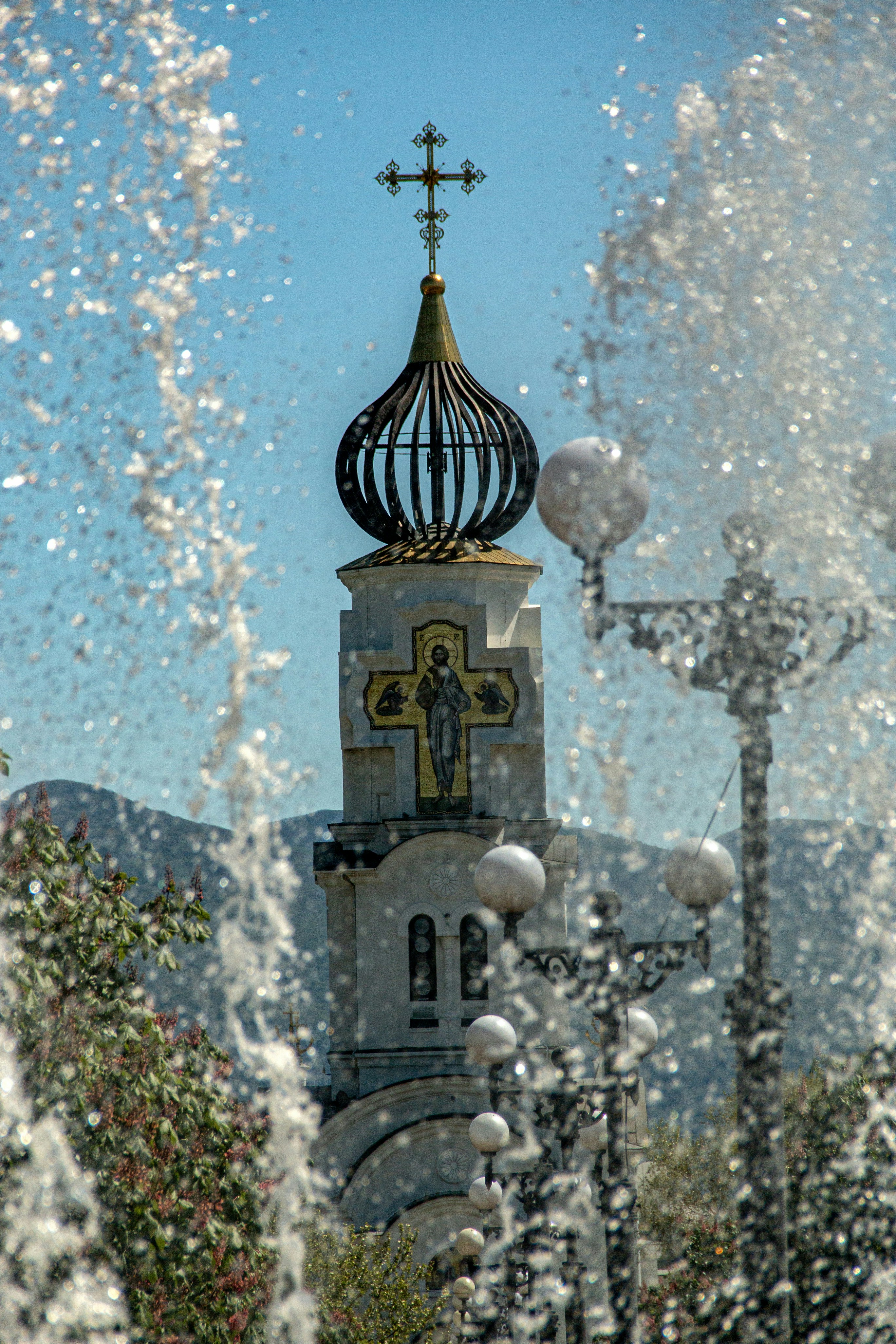 Cross-Topped Onion Dome Framed by Spraying Fountains Under a Pristine Blue Sky