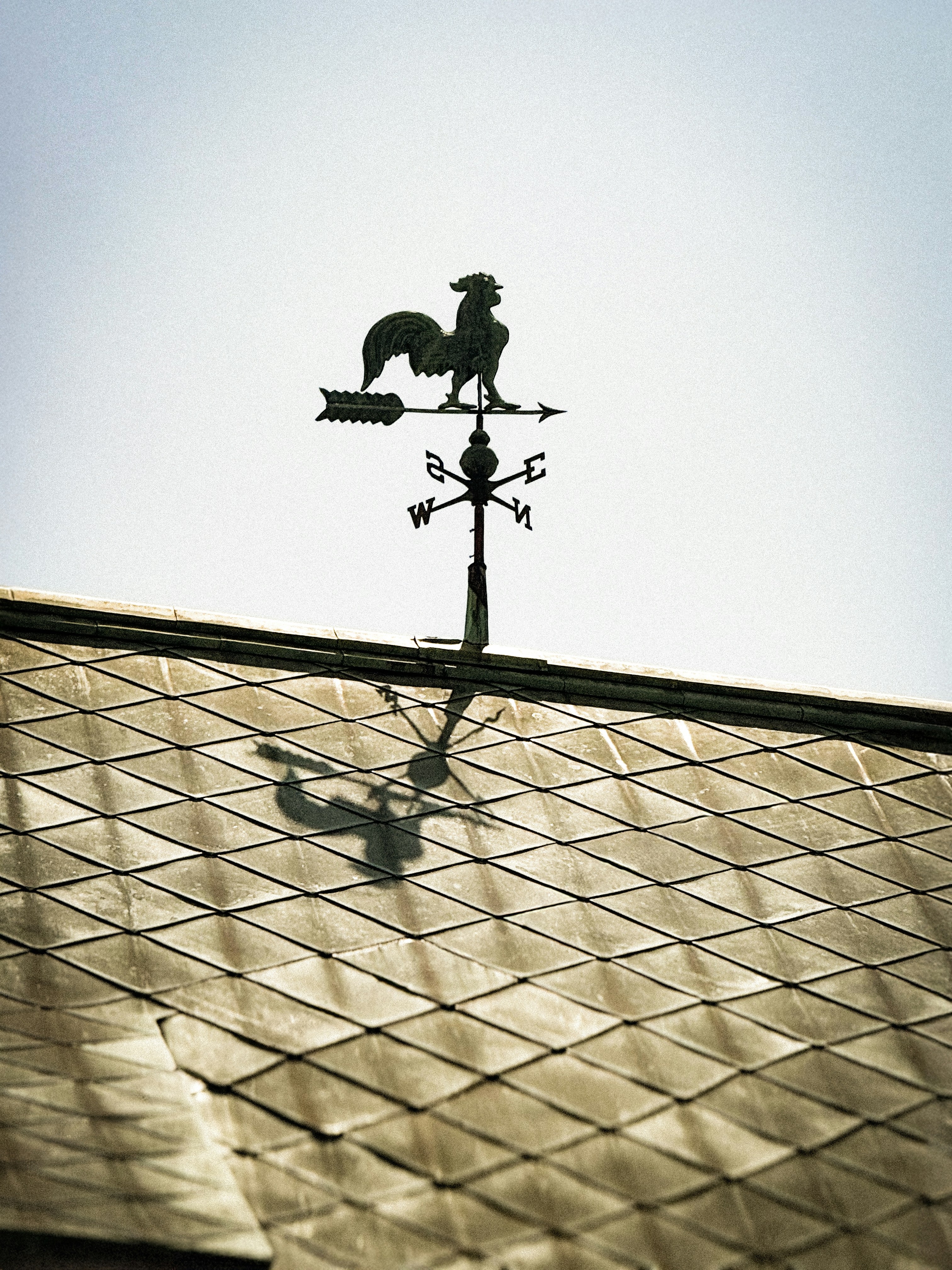 Rooster Weathervane Above Diamond Tiles: A Quiet Roof Shadow Play