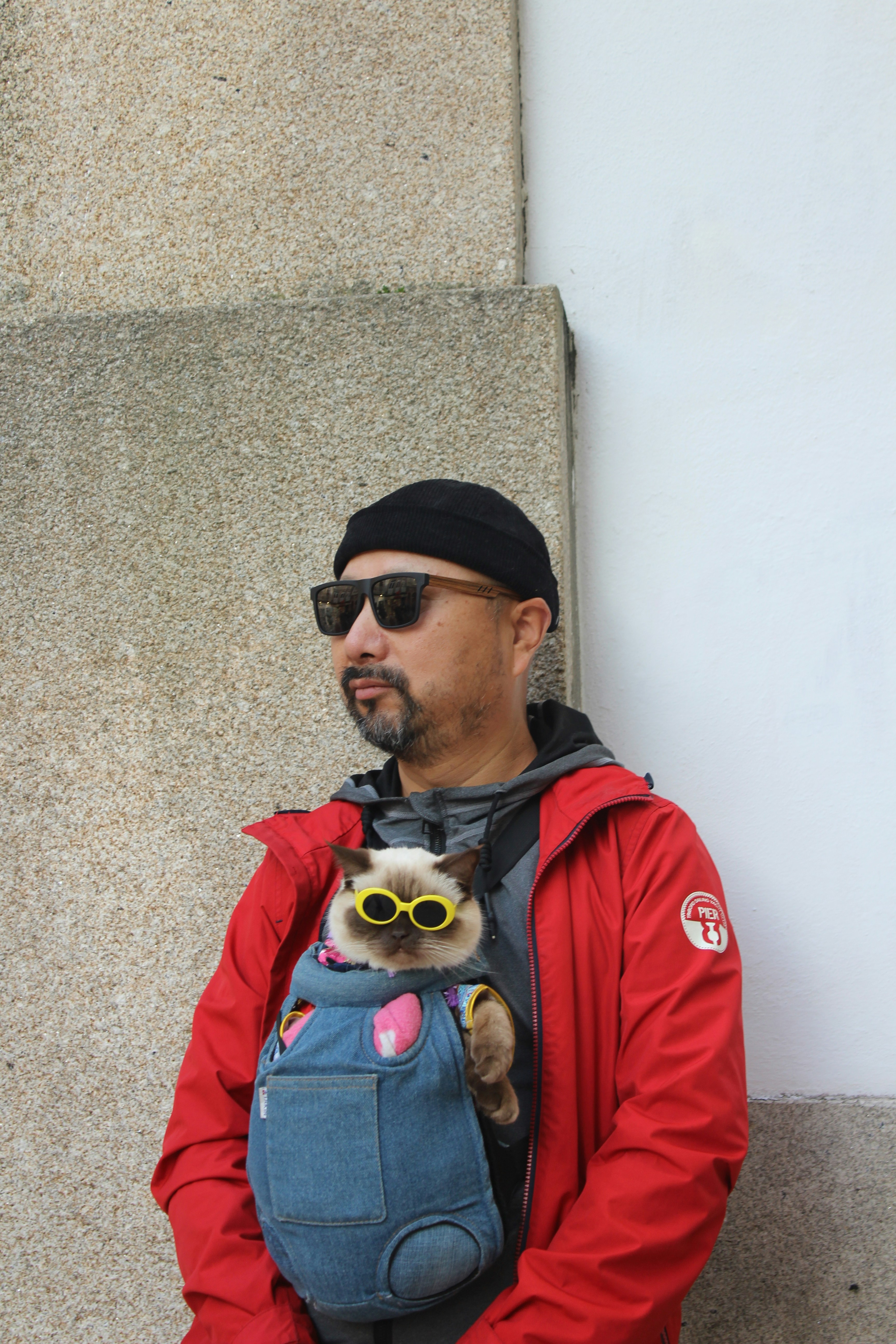 Red-Jacketed Traveler and Sunglass Pose with Mini Backpack Cathexis