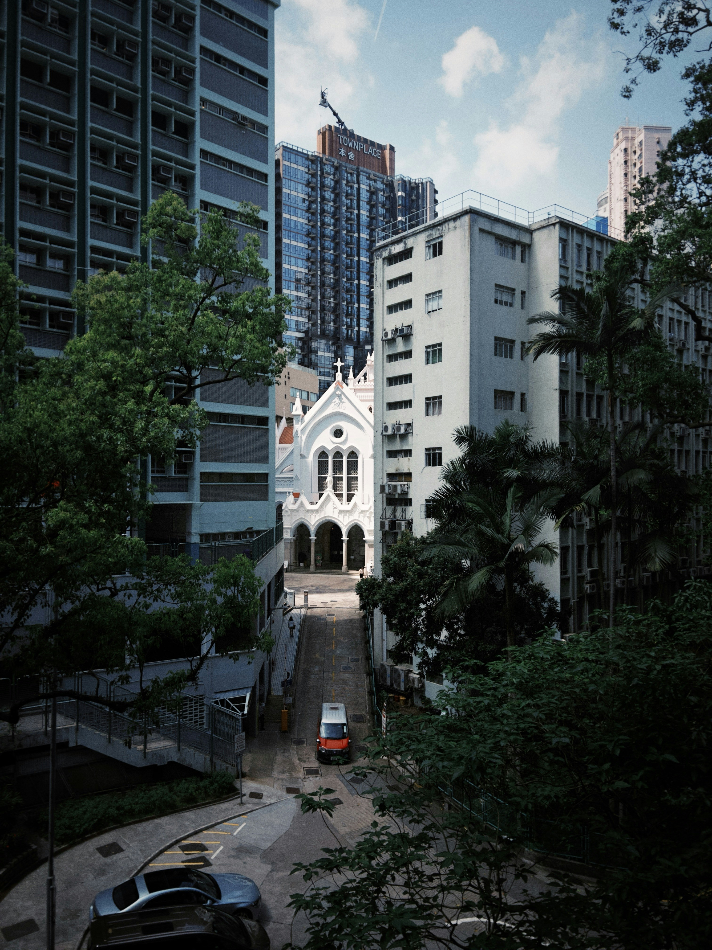Between Towers: A White Neo-Gothic Chapel Framed by Urban Giants