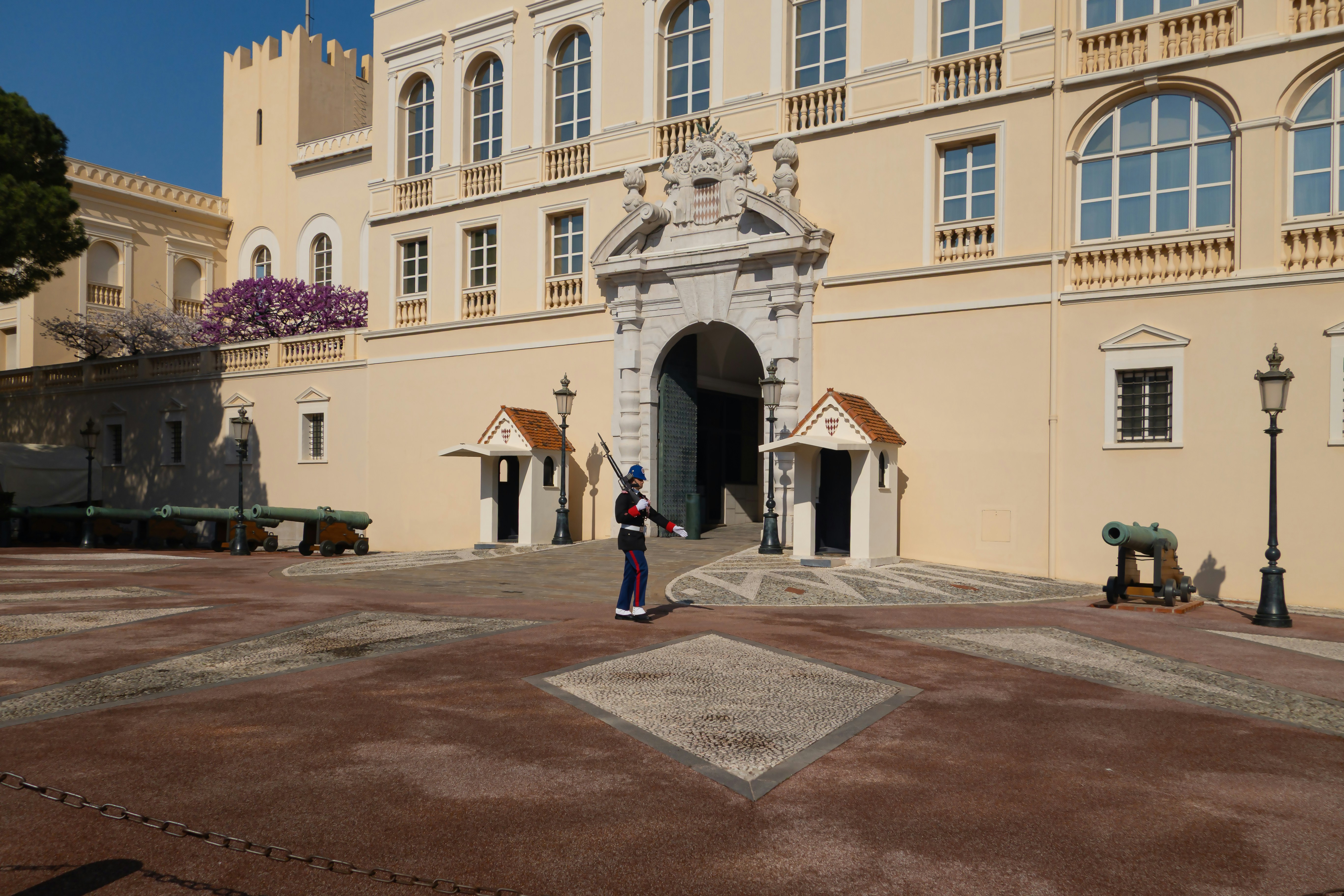 A guard stands at the entrance of a grand building.