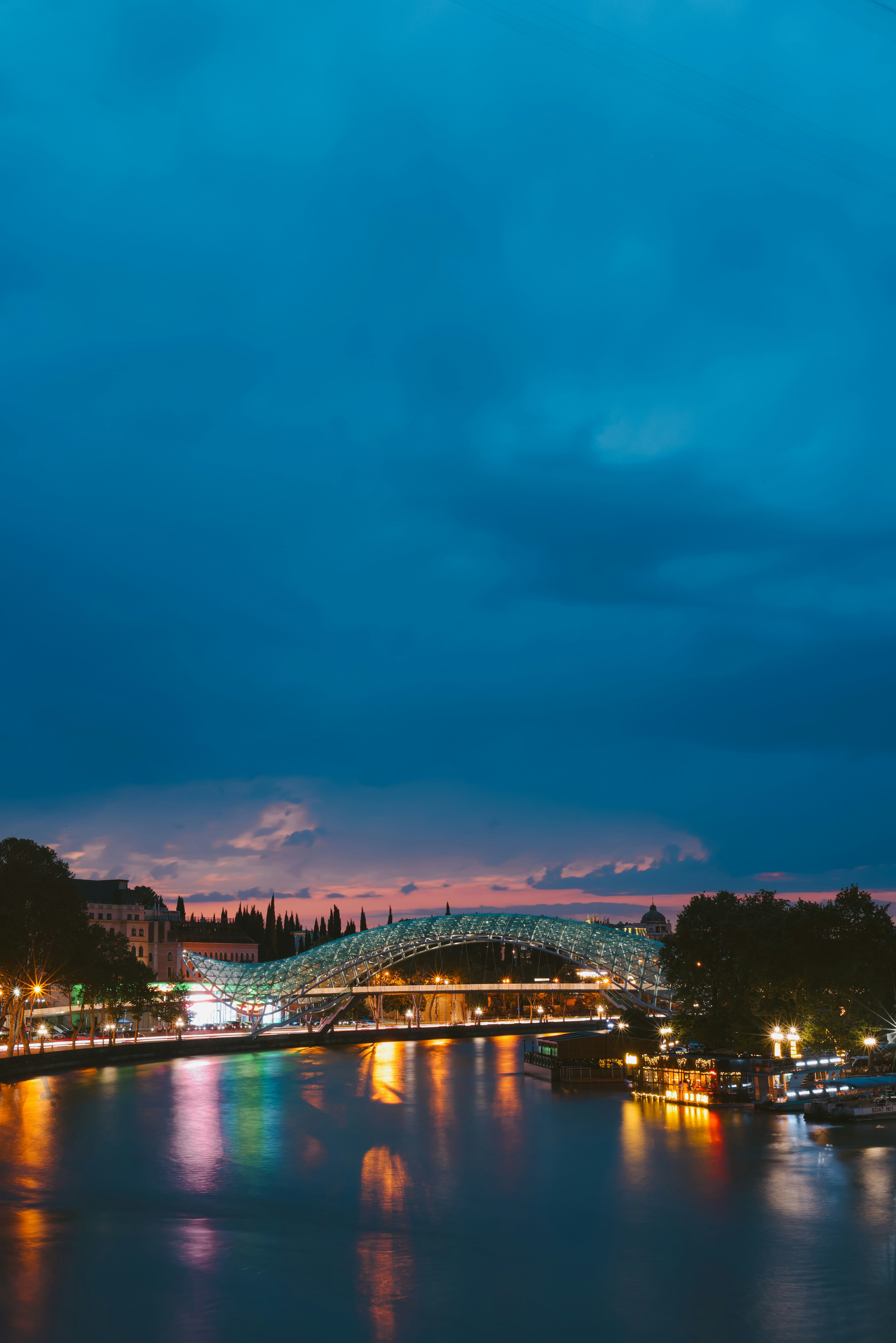 A lit-up bridge reflects in the water at dusk. photo – Free Wallpaper ...