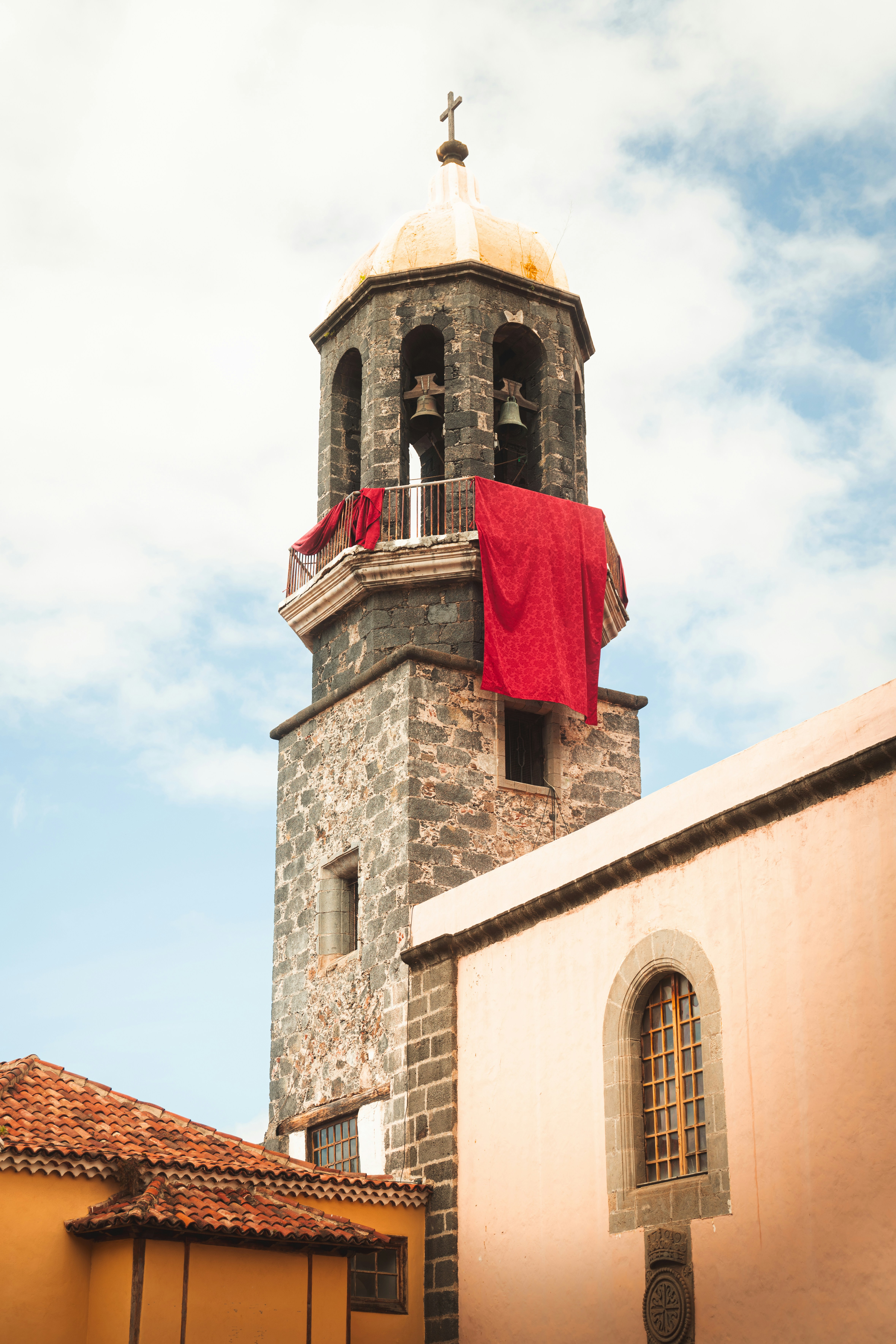 Crimson Drapery on a Weathered Bell Tower Beneath a Bright Sky