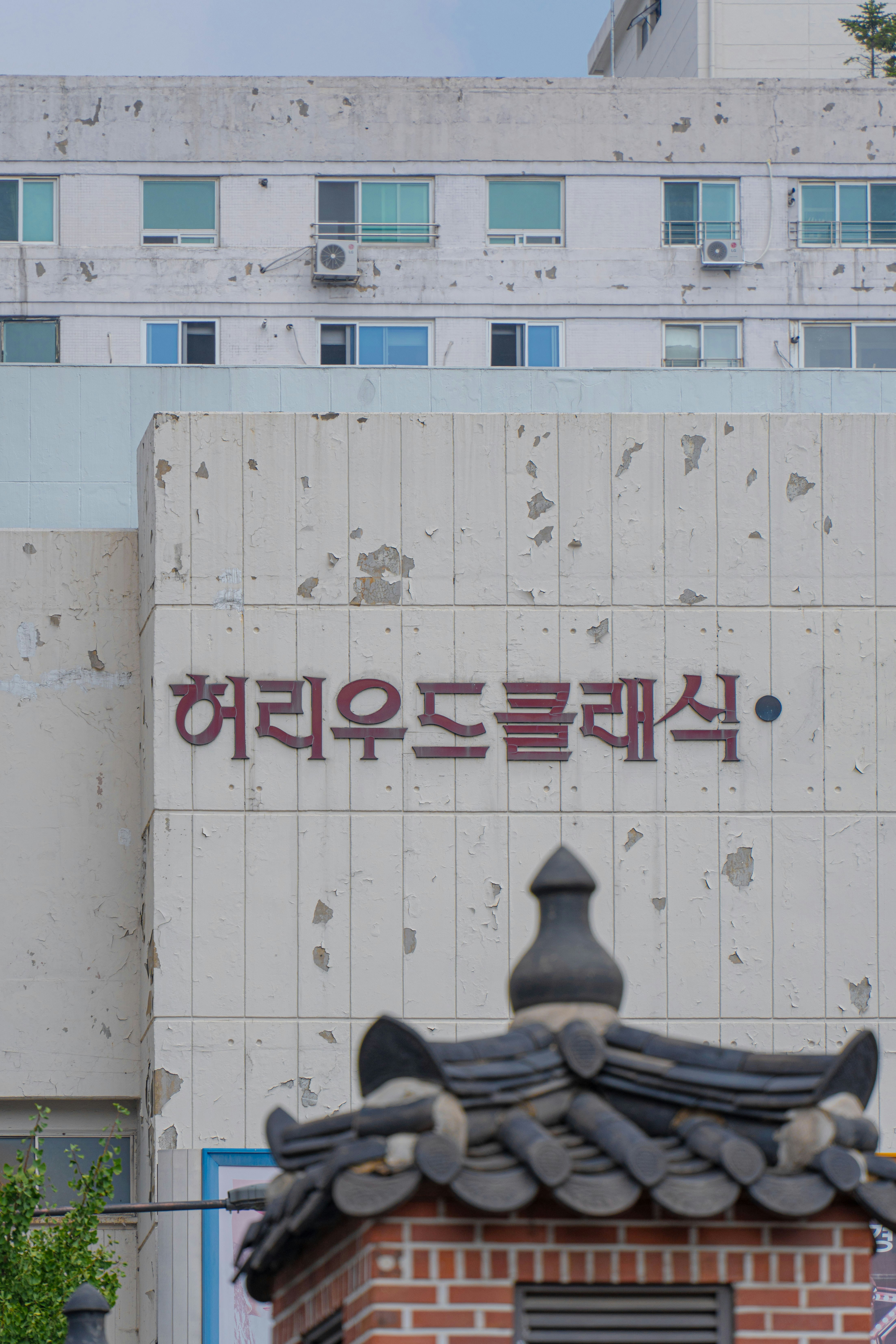 Korean Script on Weathered Facade Framed by a Traditional Tile Roof