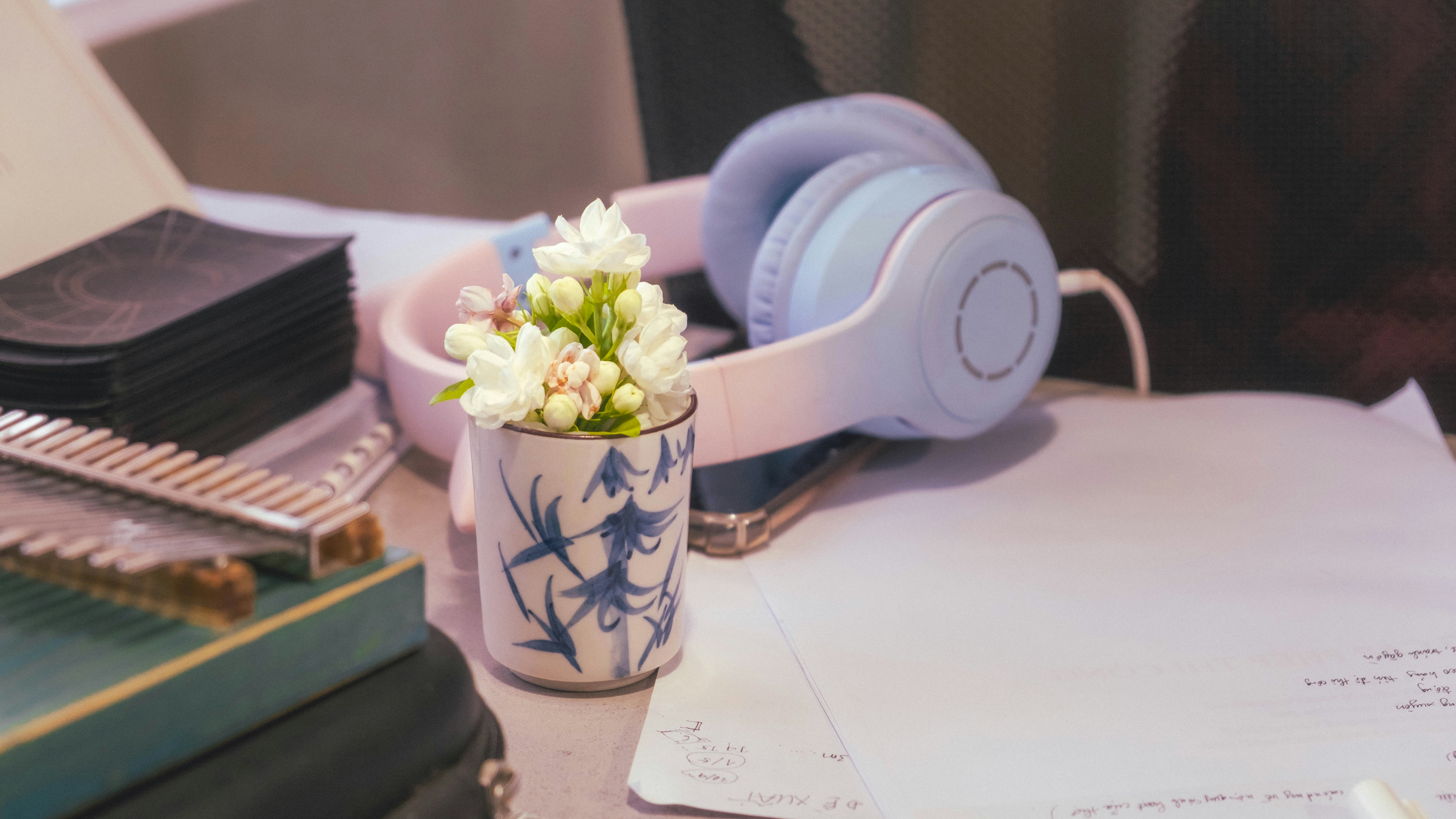 Pastel headphones and a flowering mug on a cluttered desk