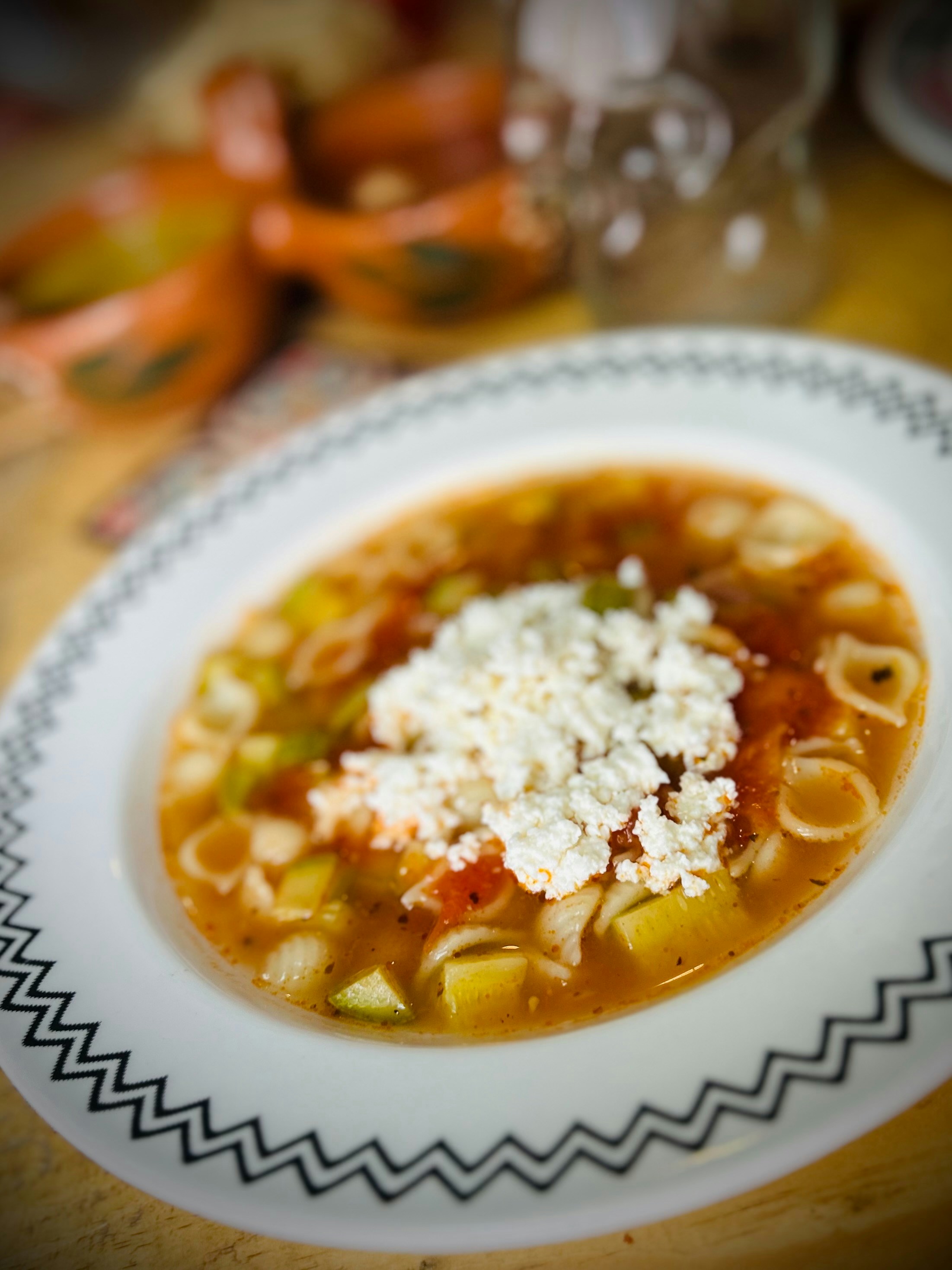 A bowl of soup is topped with cheese.