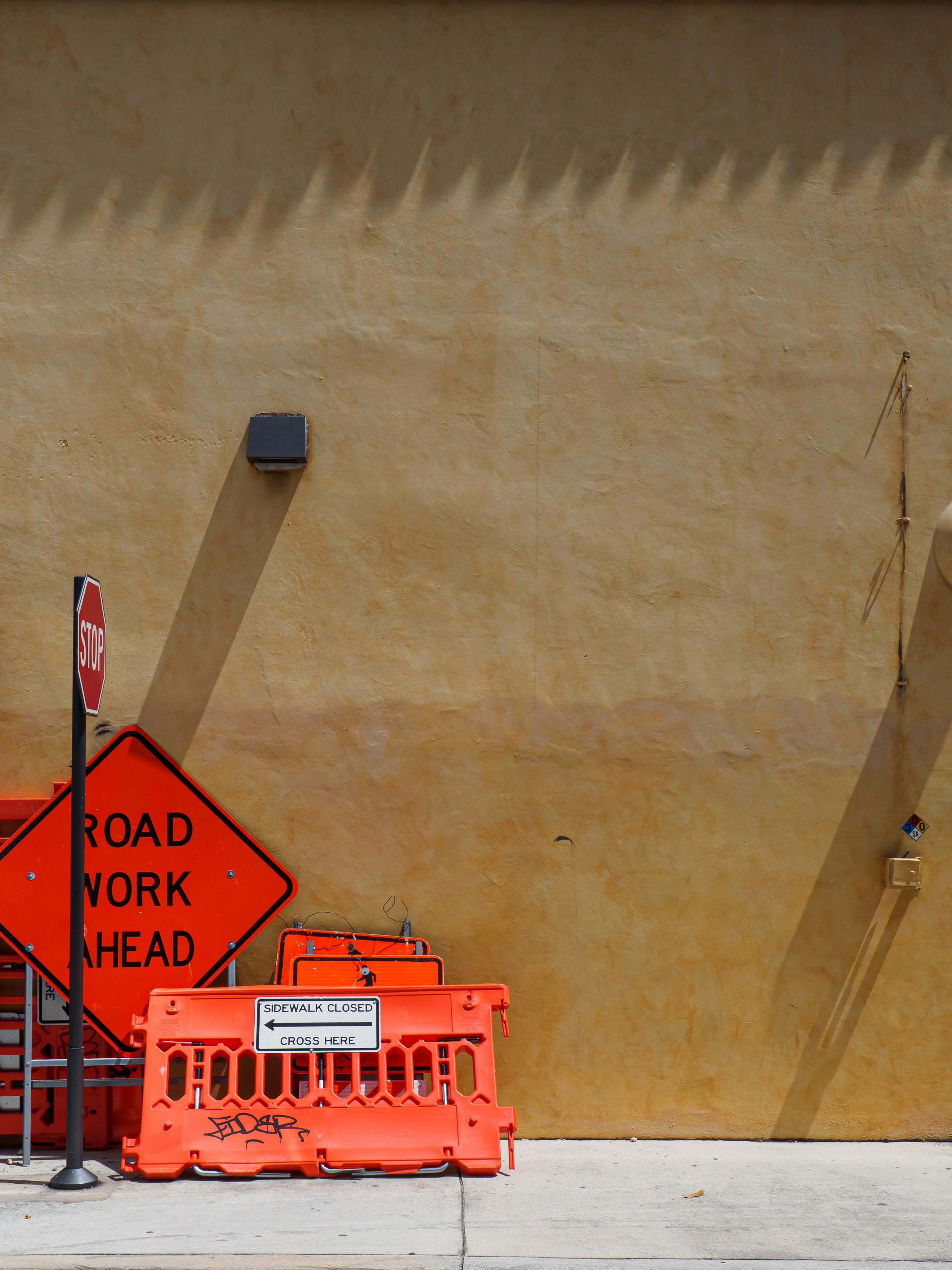 Road work signs stand beside a brown wall. photo – Free Usa Image on ...