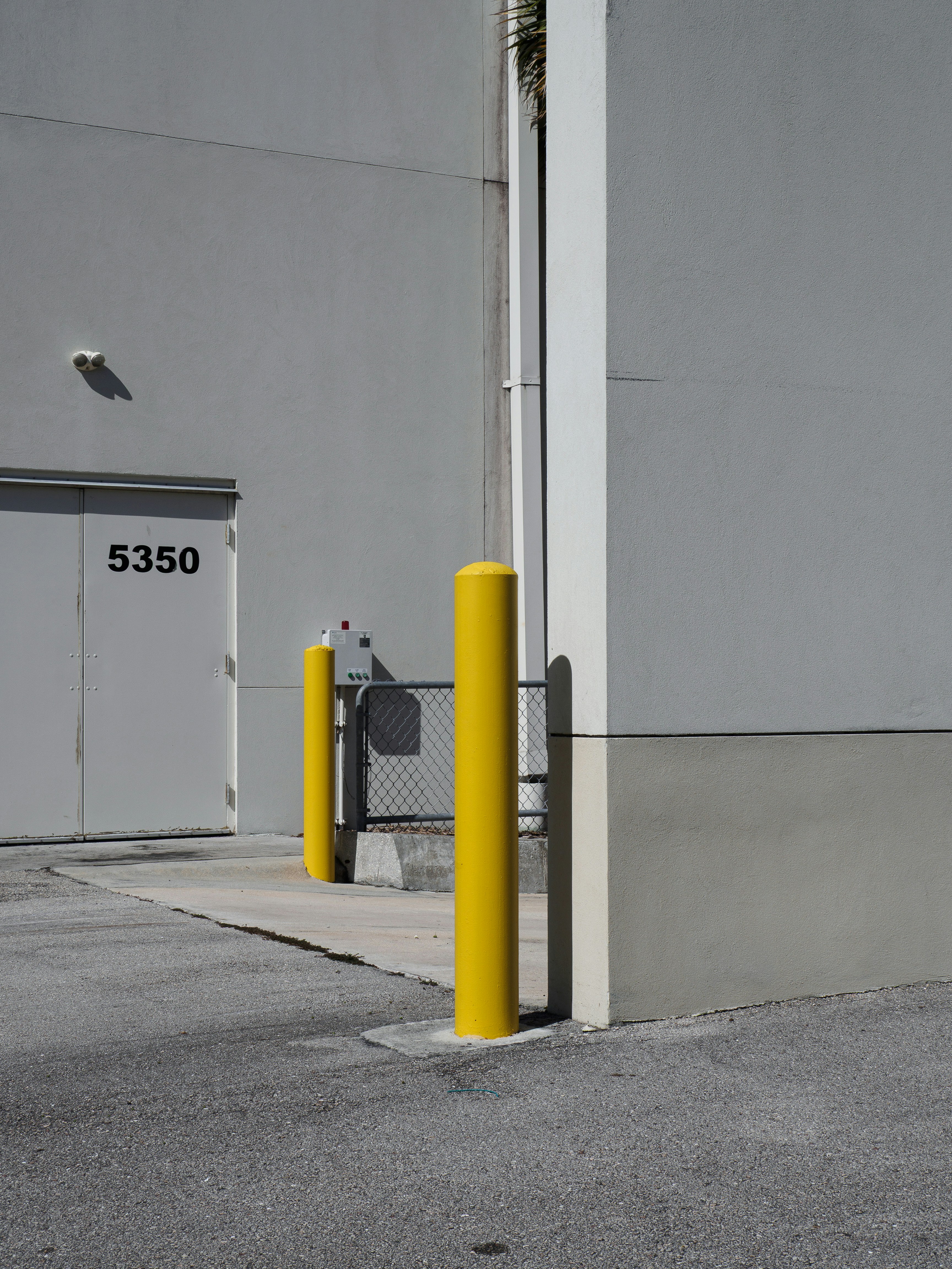 Sunlit Sentinel: Yellow Bollards Guard a Quiet Industrial Threshold