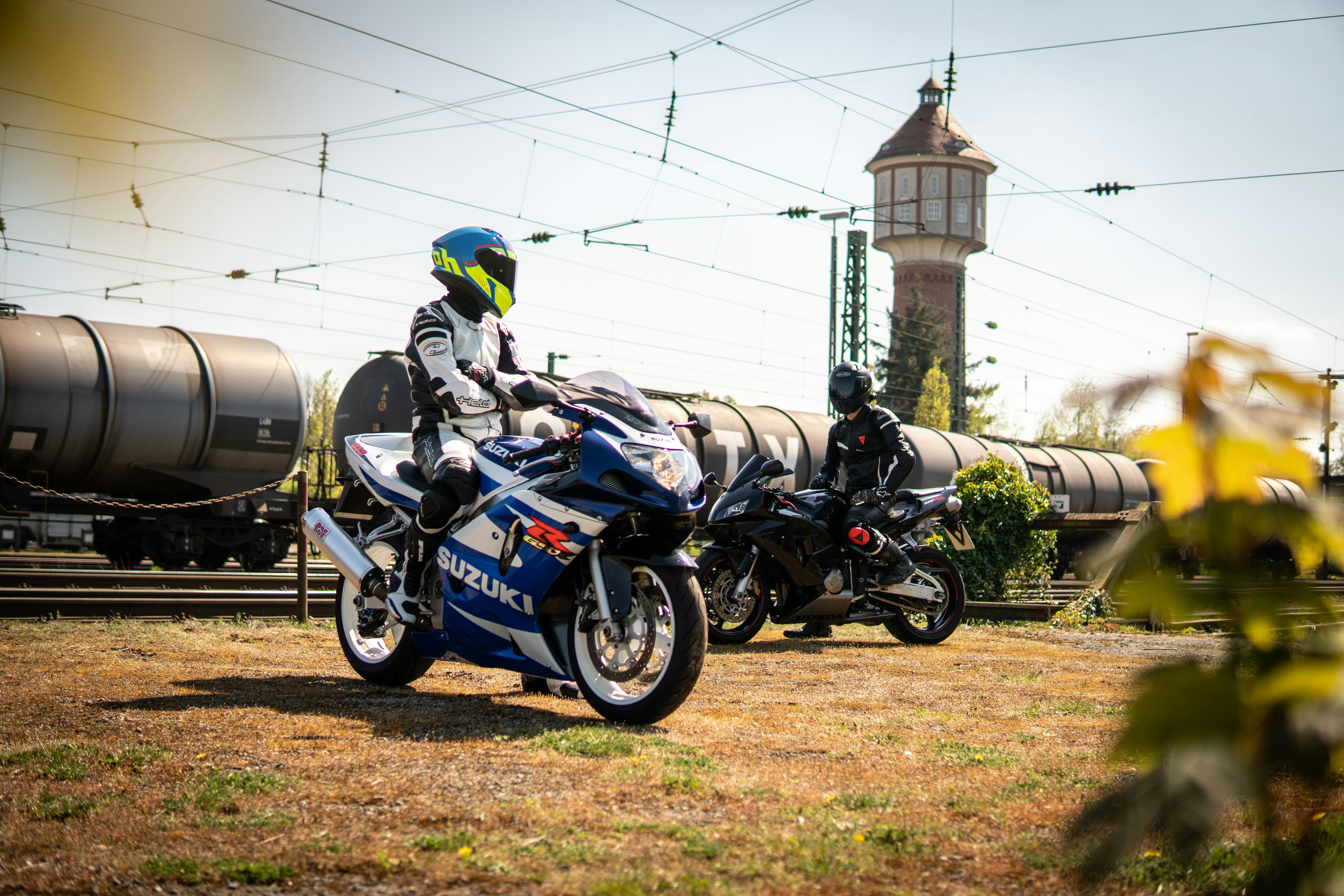 Blue Sprint by the Rails: Suzuki Riders Pause Amid Industrial Tracks