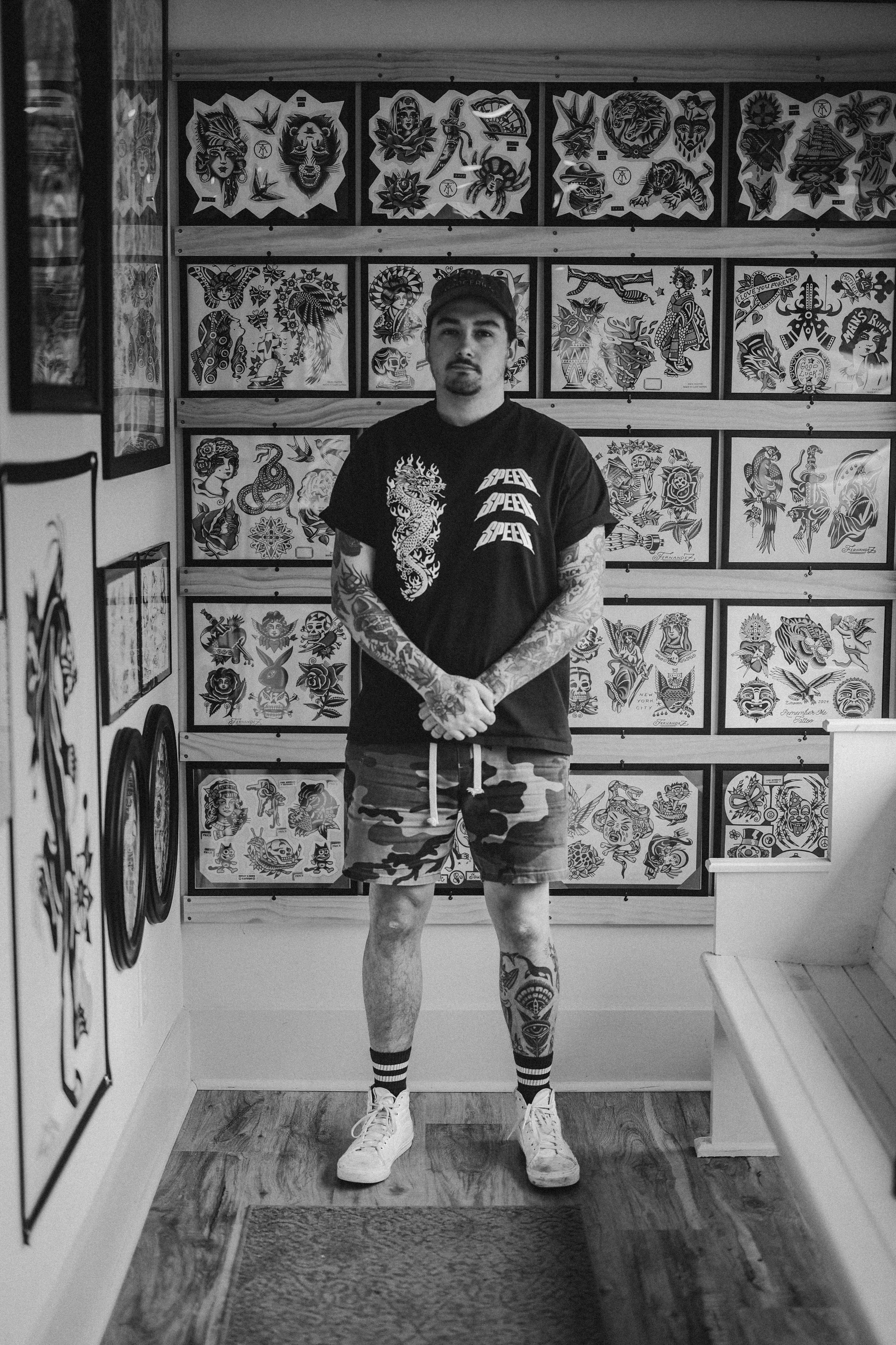 A tattooed person stands in front of tattoo flash art. photo – Free ...
