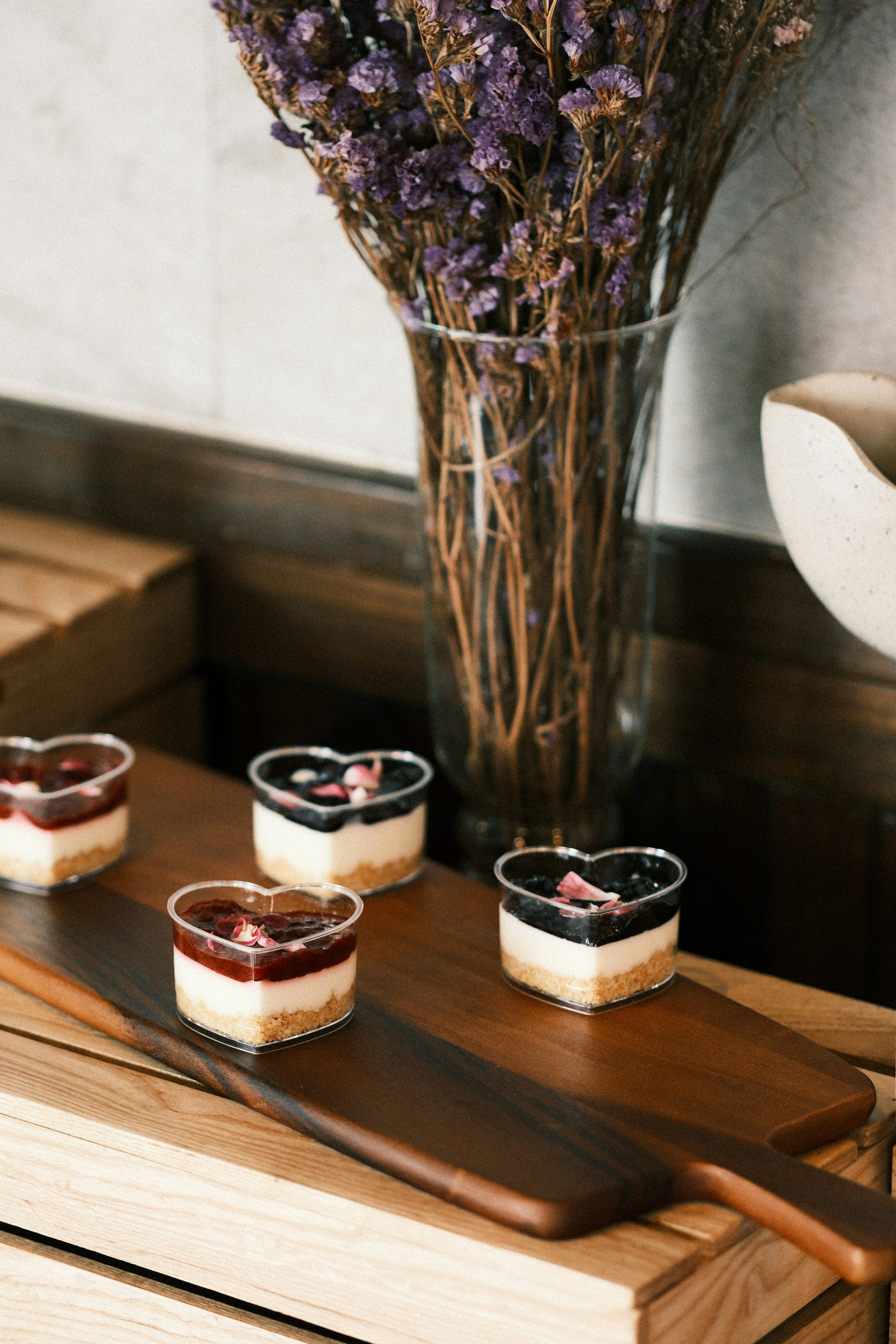 A selection of appetising heart-shaped cheesecakes are presented at a continental breakfast buffet in a hotel in Pattaya, Thailand | Heart-shaped cheesecakes sit beside dried flowers.