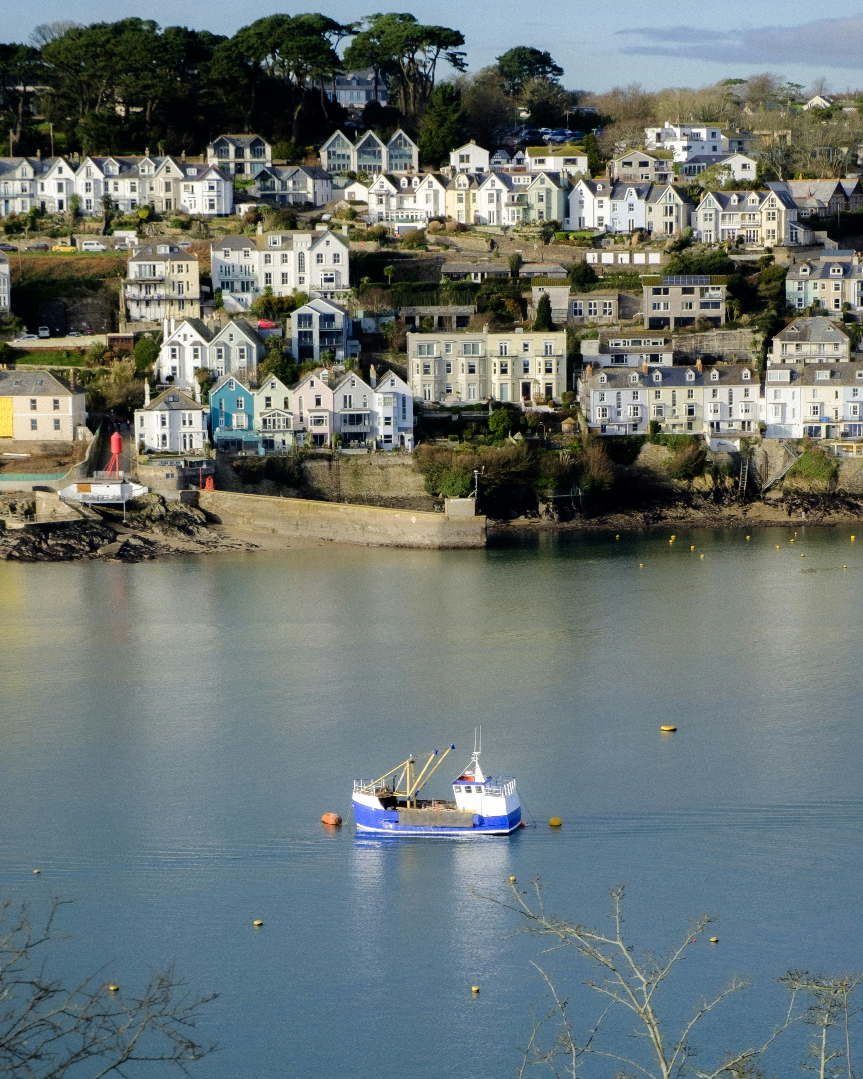 Blue Boat in a Quiet Harbor Framed by a White-Washed Coastal Village
