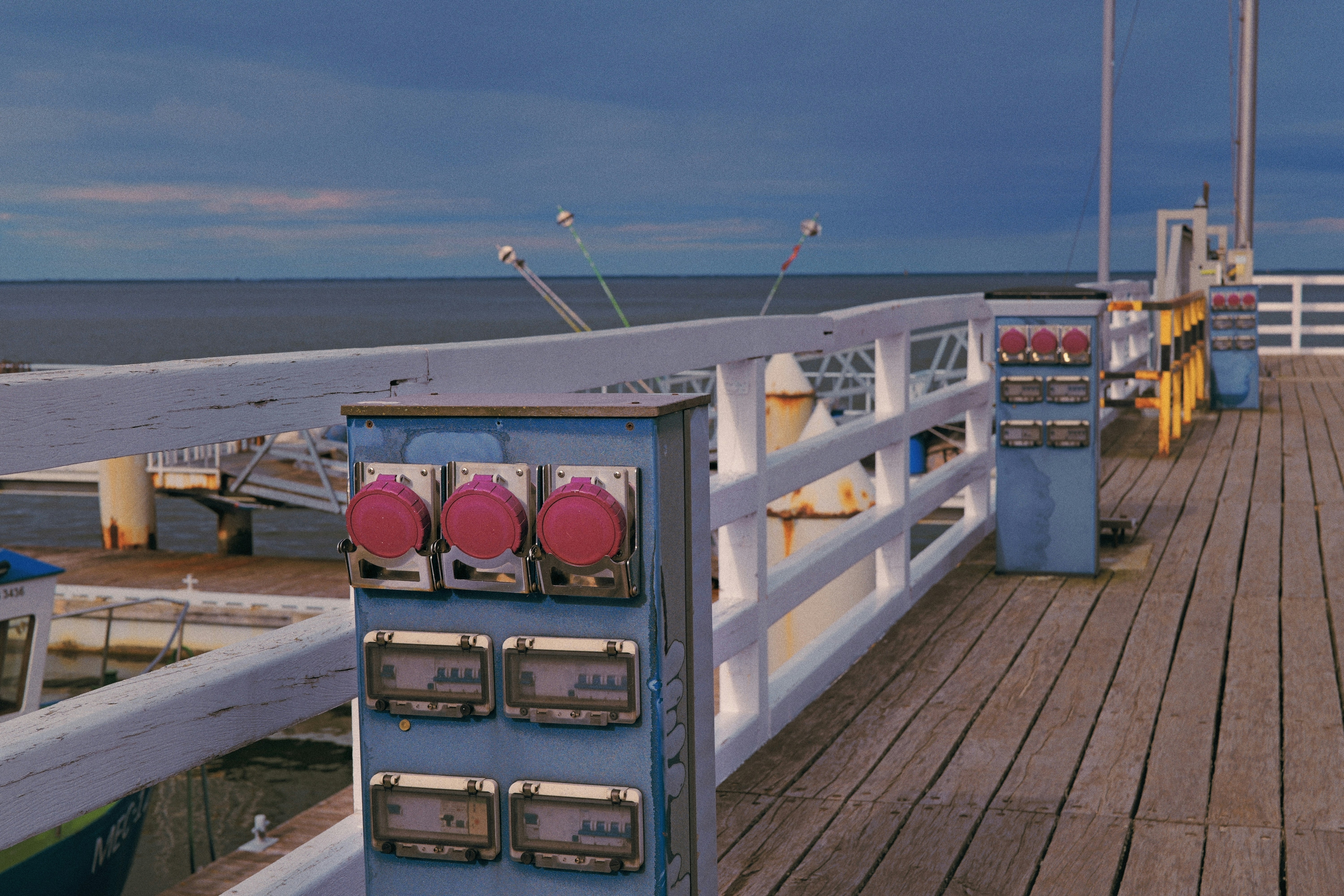 Pastel Control Panels Framing a Weathered Pier Against a Calm Horizon