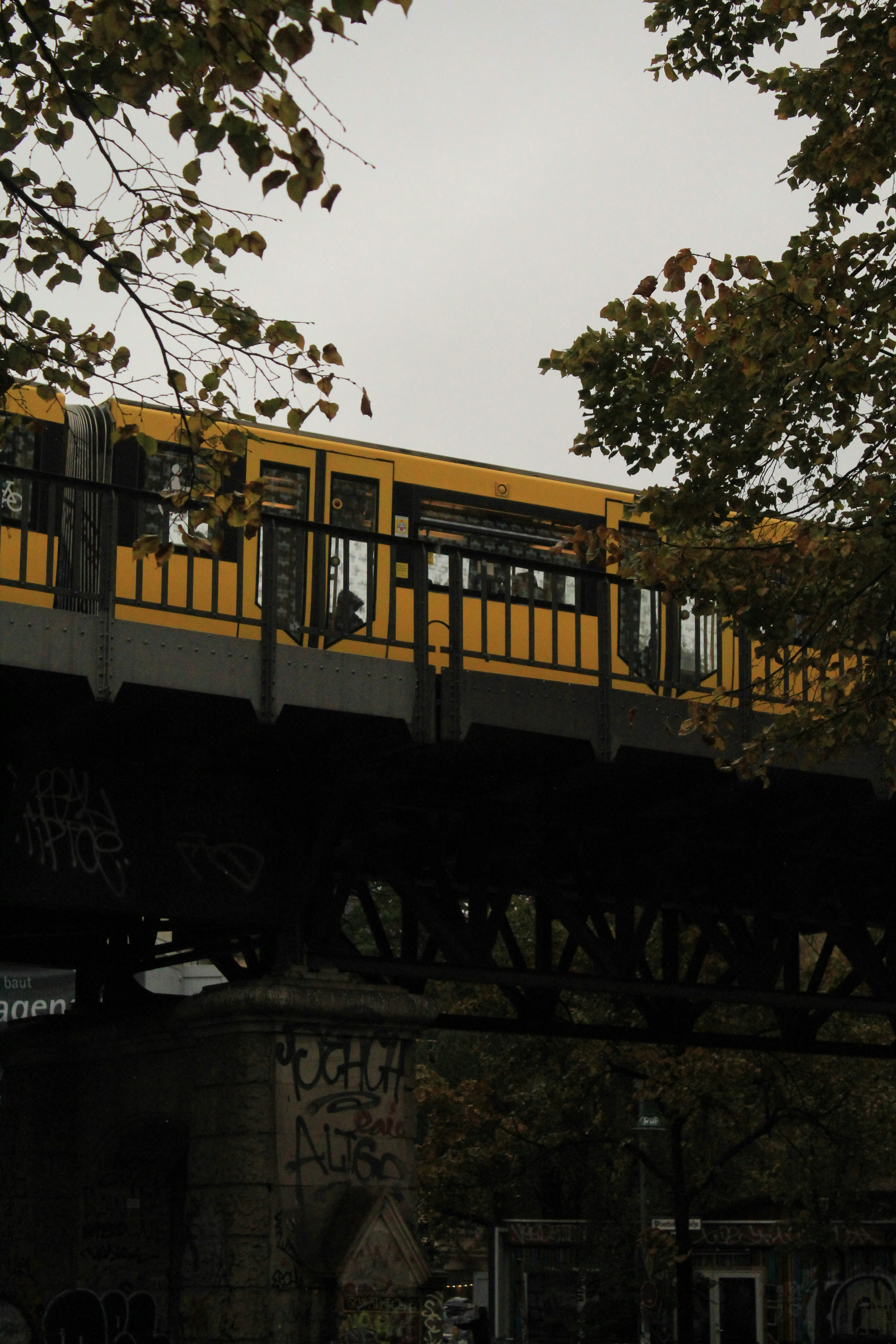 A yellow train is crossing a bridge.
