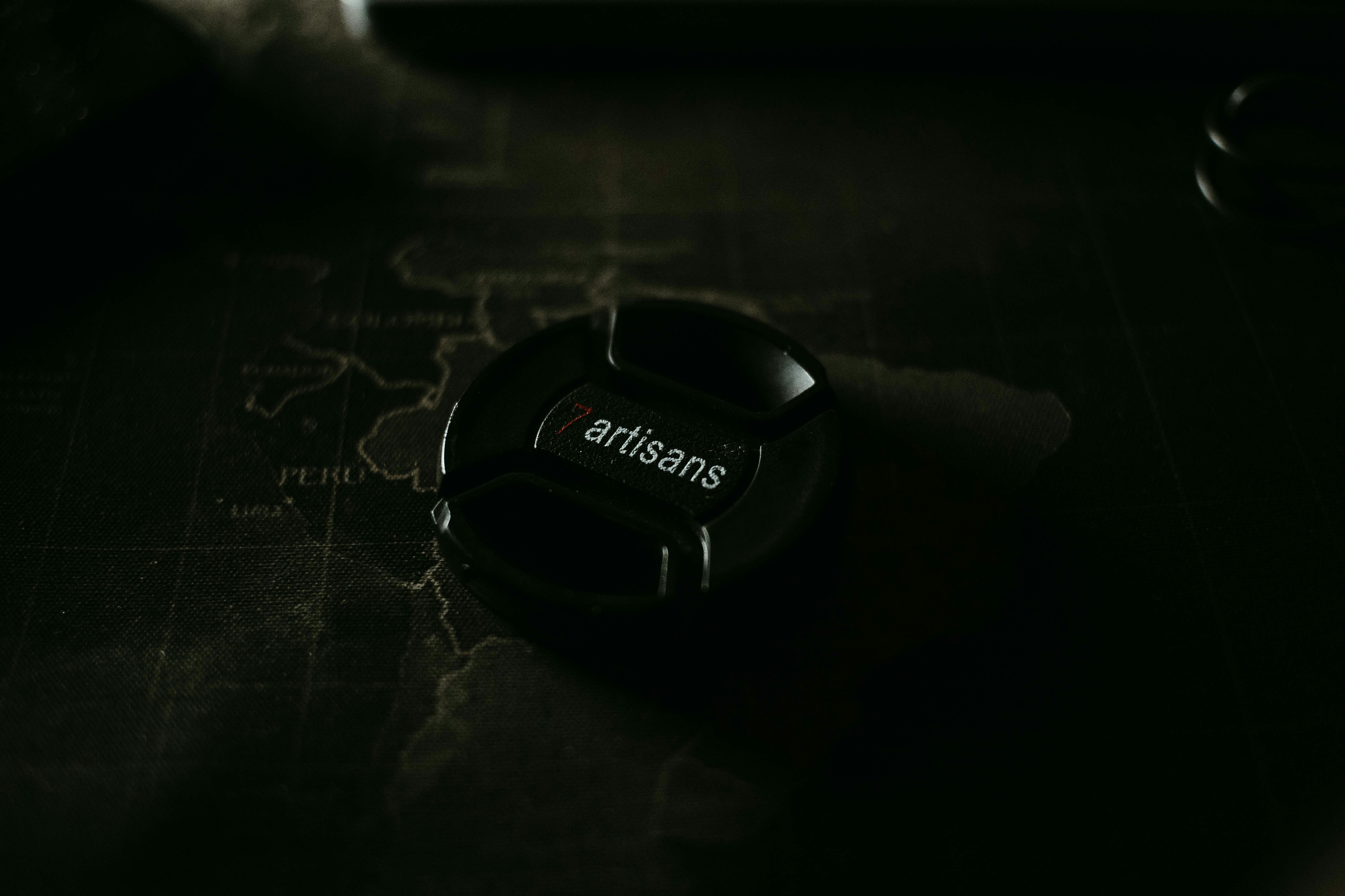 Shrouded in Darkness: A Close-Up of a Single Lens Cap on a Dim Map