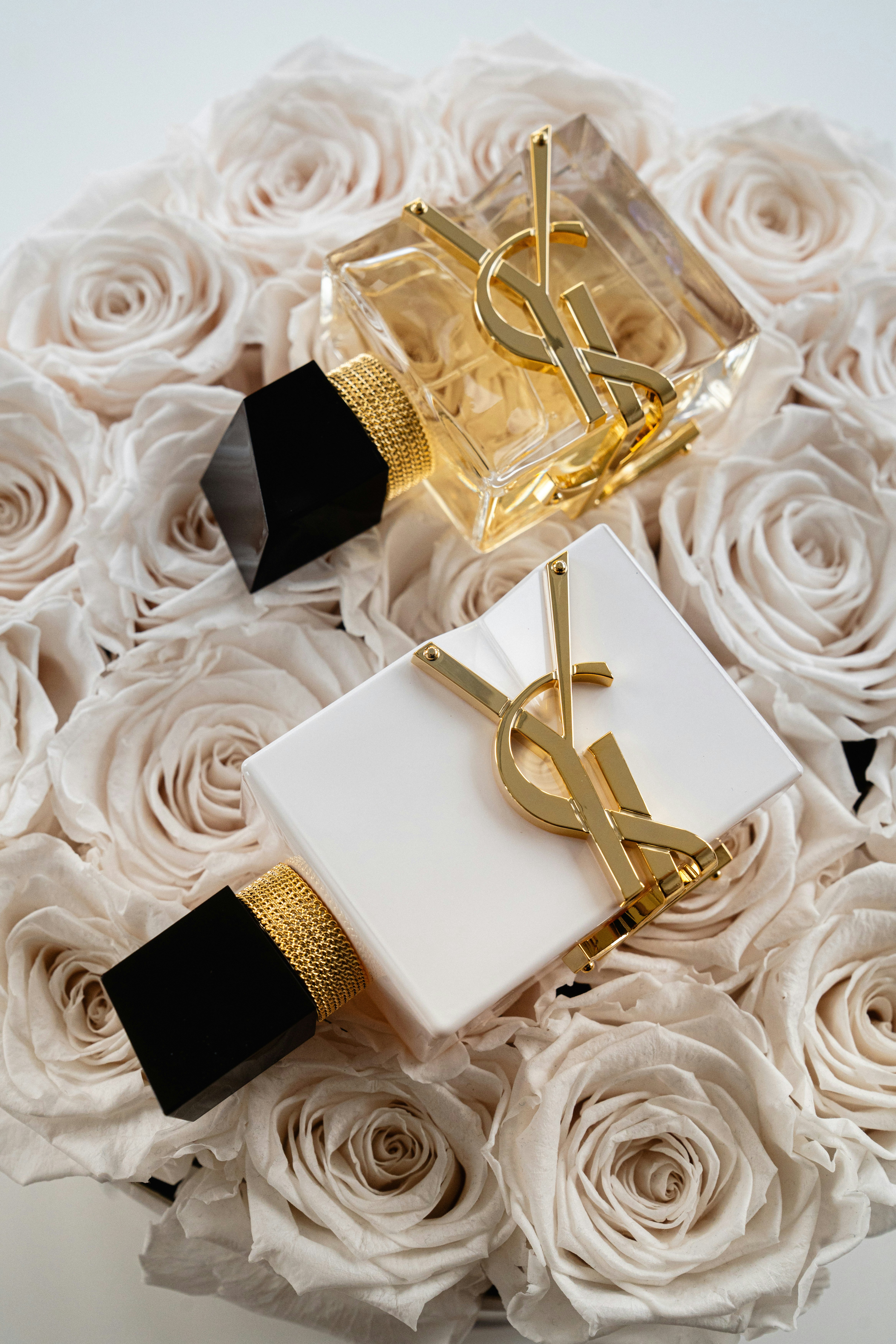 Two ysl perfume bottles rest among white roses. photo – Free Rose ...