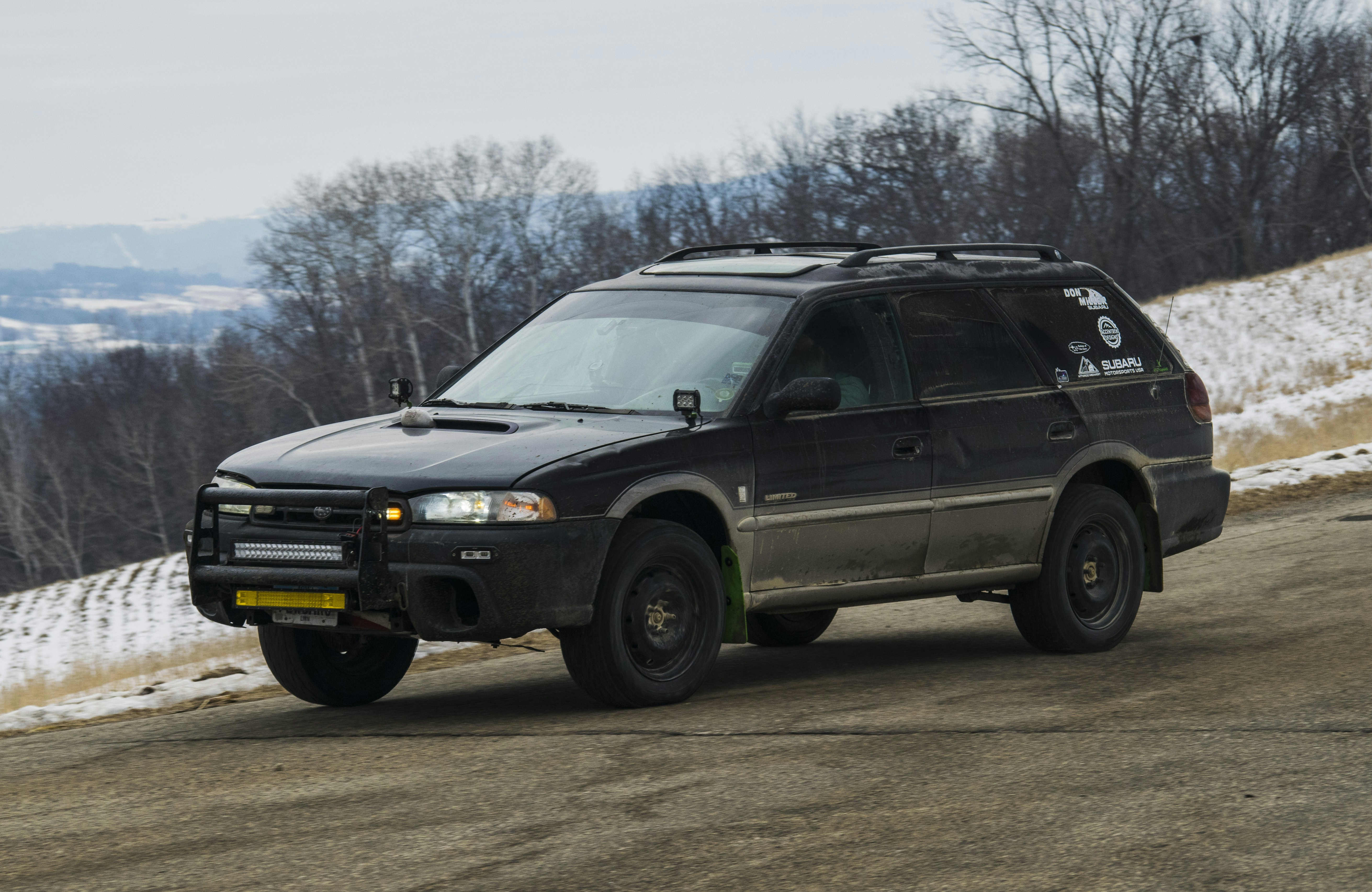 Mud-Splattered SUV Navigates a Snow-Kissed Hill Road