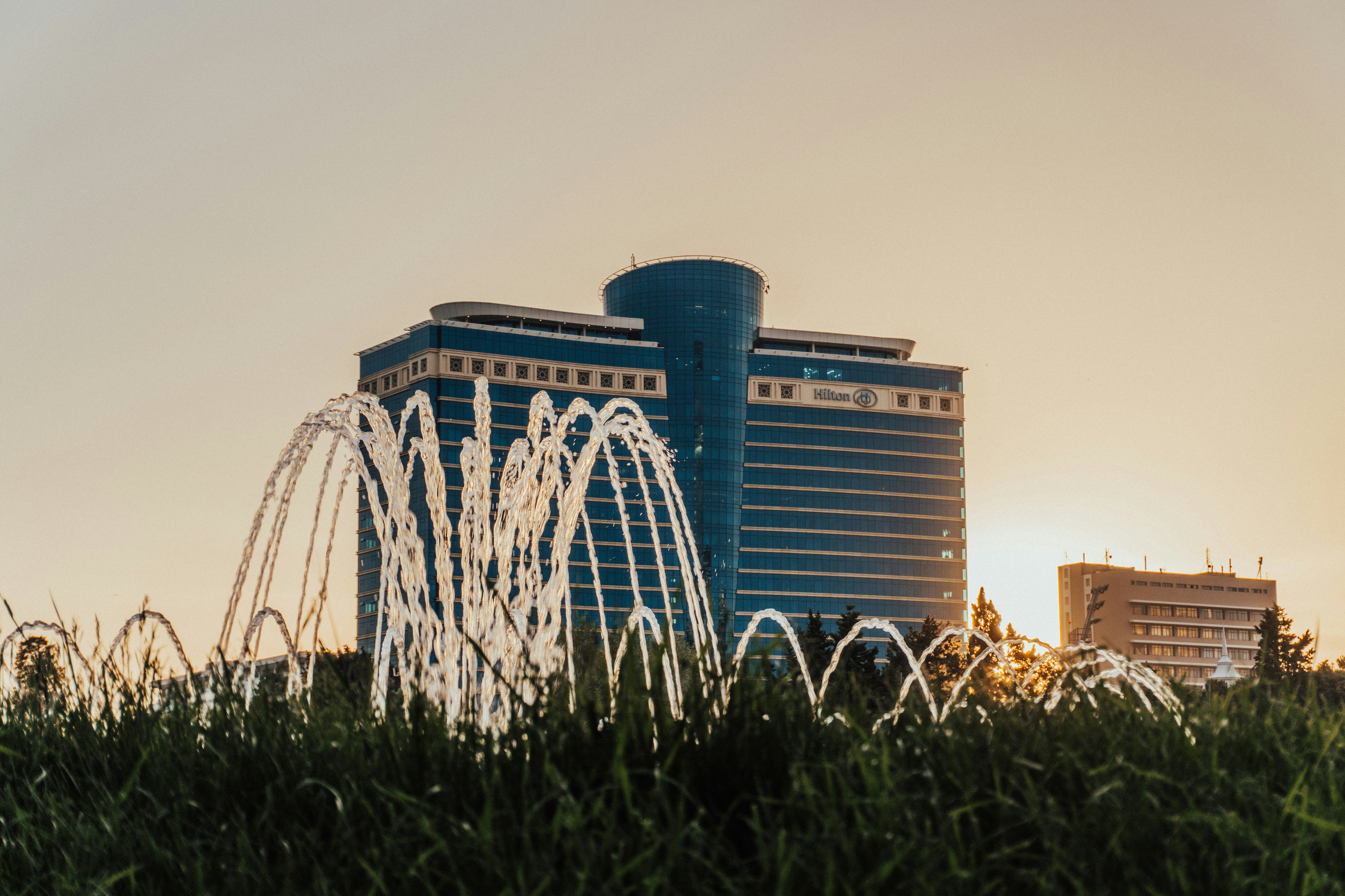 Golden Hour Spray: Fountain Arcs Framing a Modern Skyline
