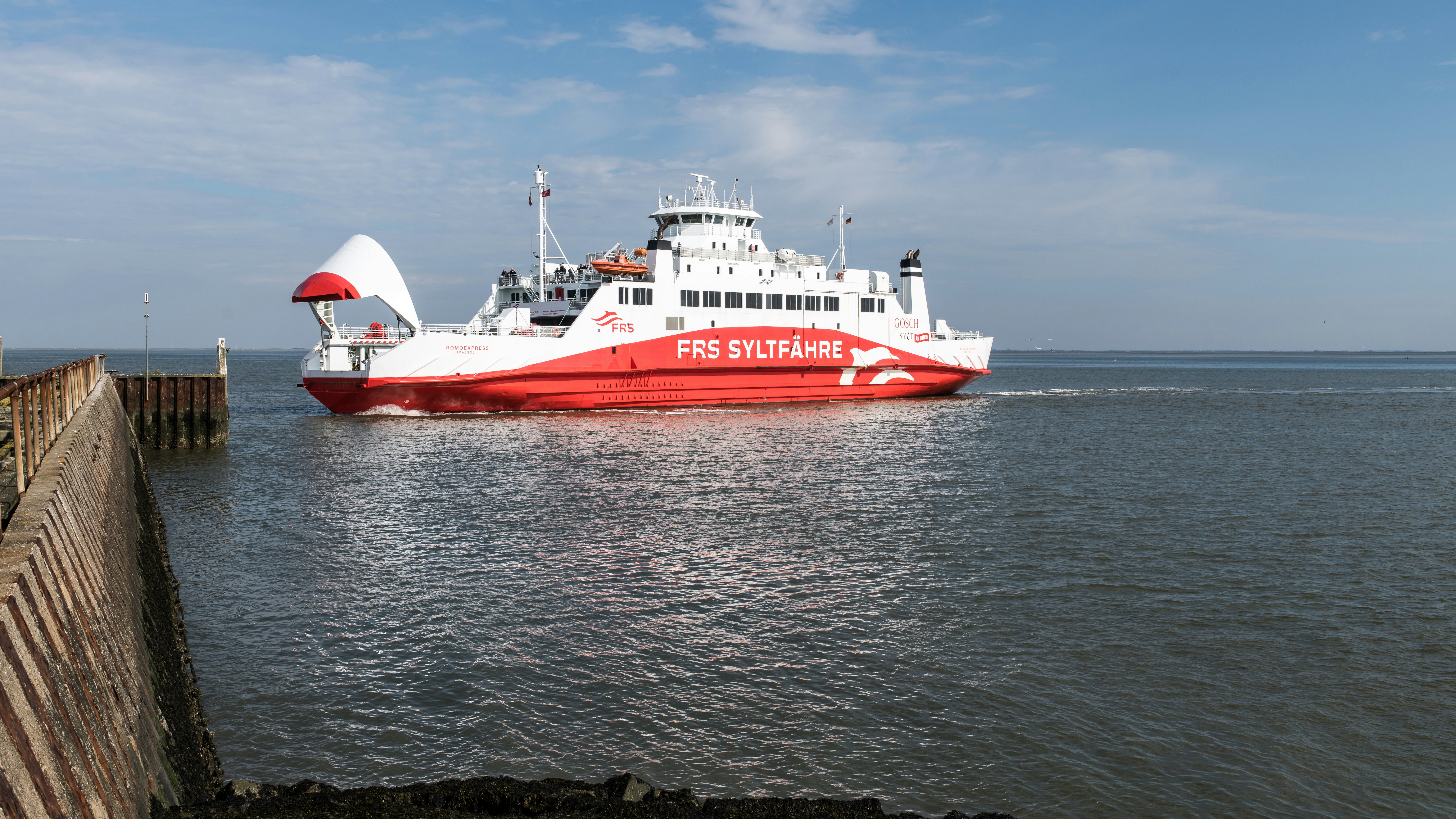 A ferry boat is sailing on a calm body of water.