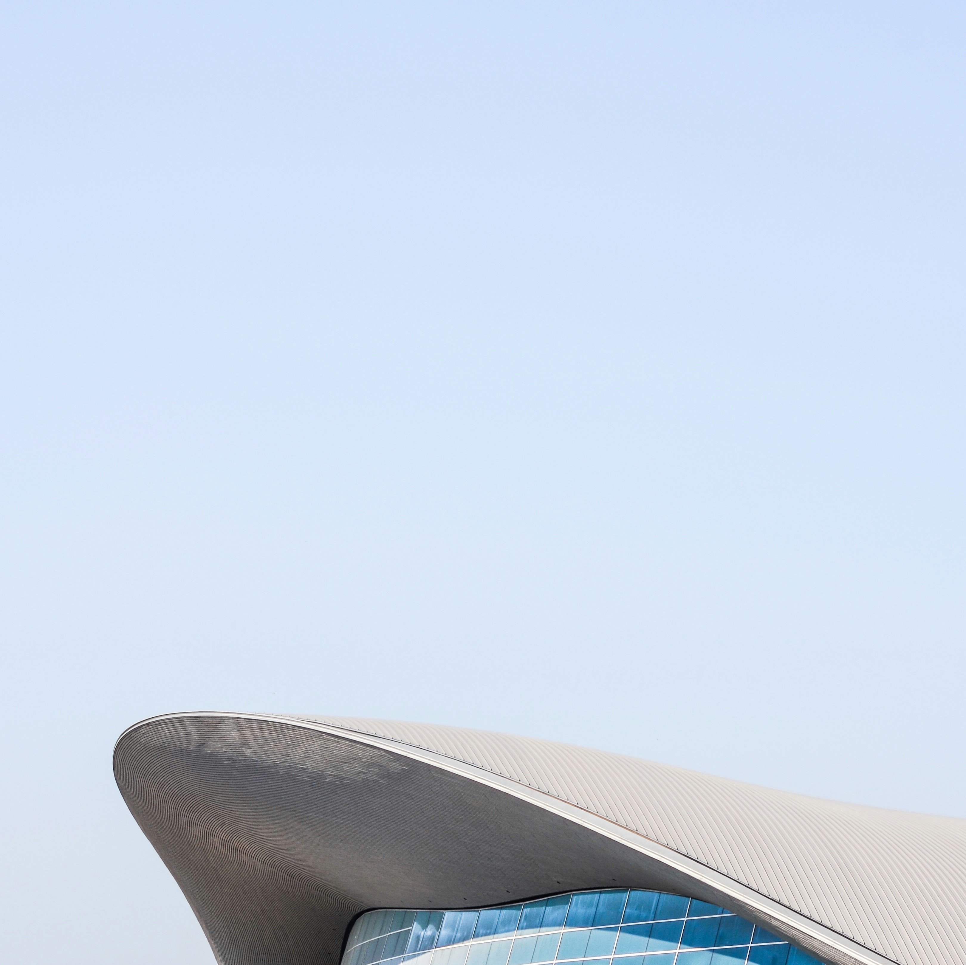 Curved Roofline and Glass Facade Beneath an Open Sky