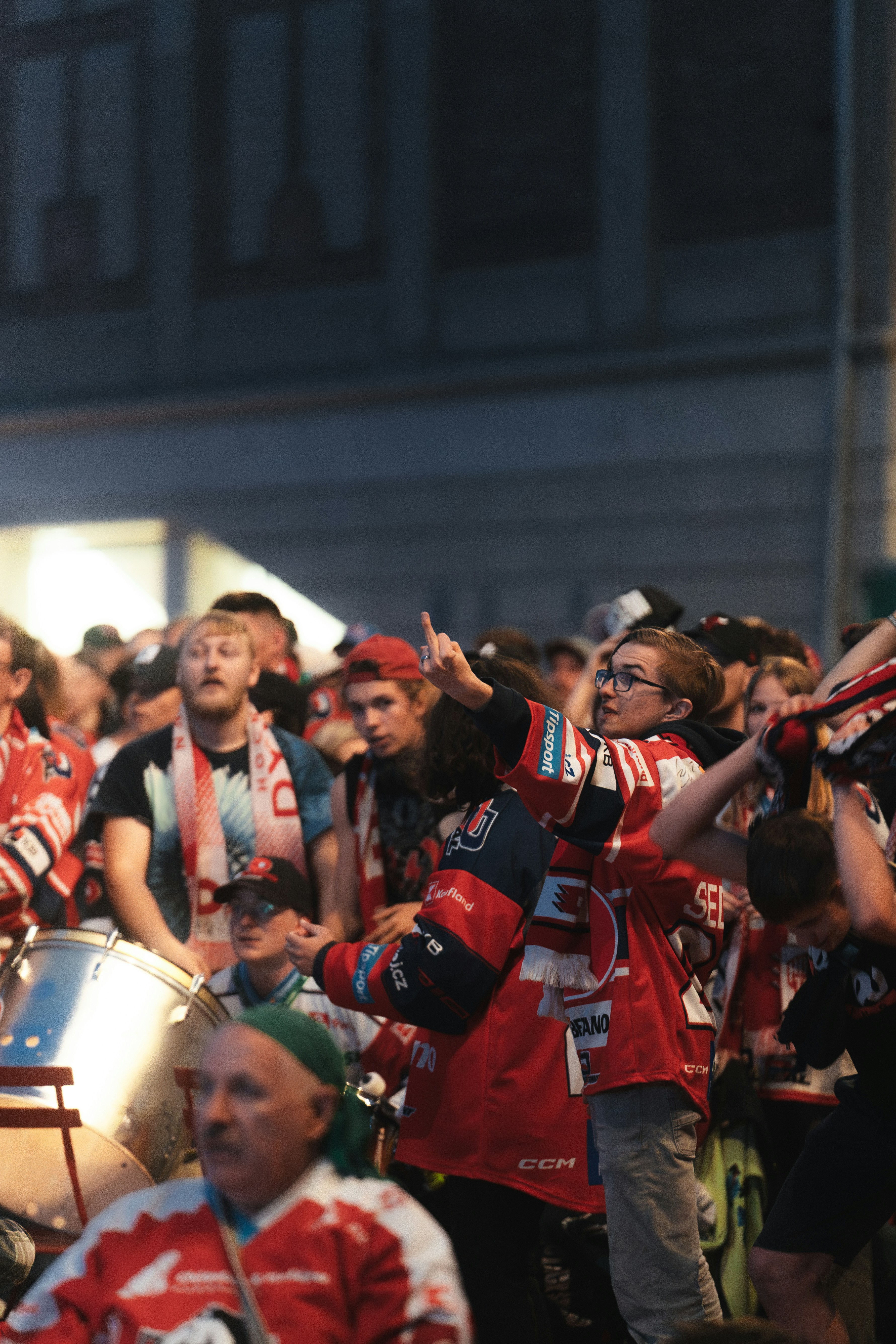 Young ice hockey fan in a crowd of disappinted people giving his middle finger to other hockey team after they scored a goal | Fans celebrate a victory in their hockey jerseys.