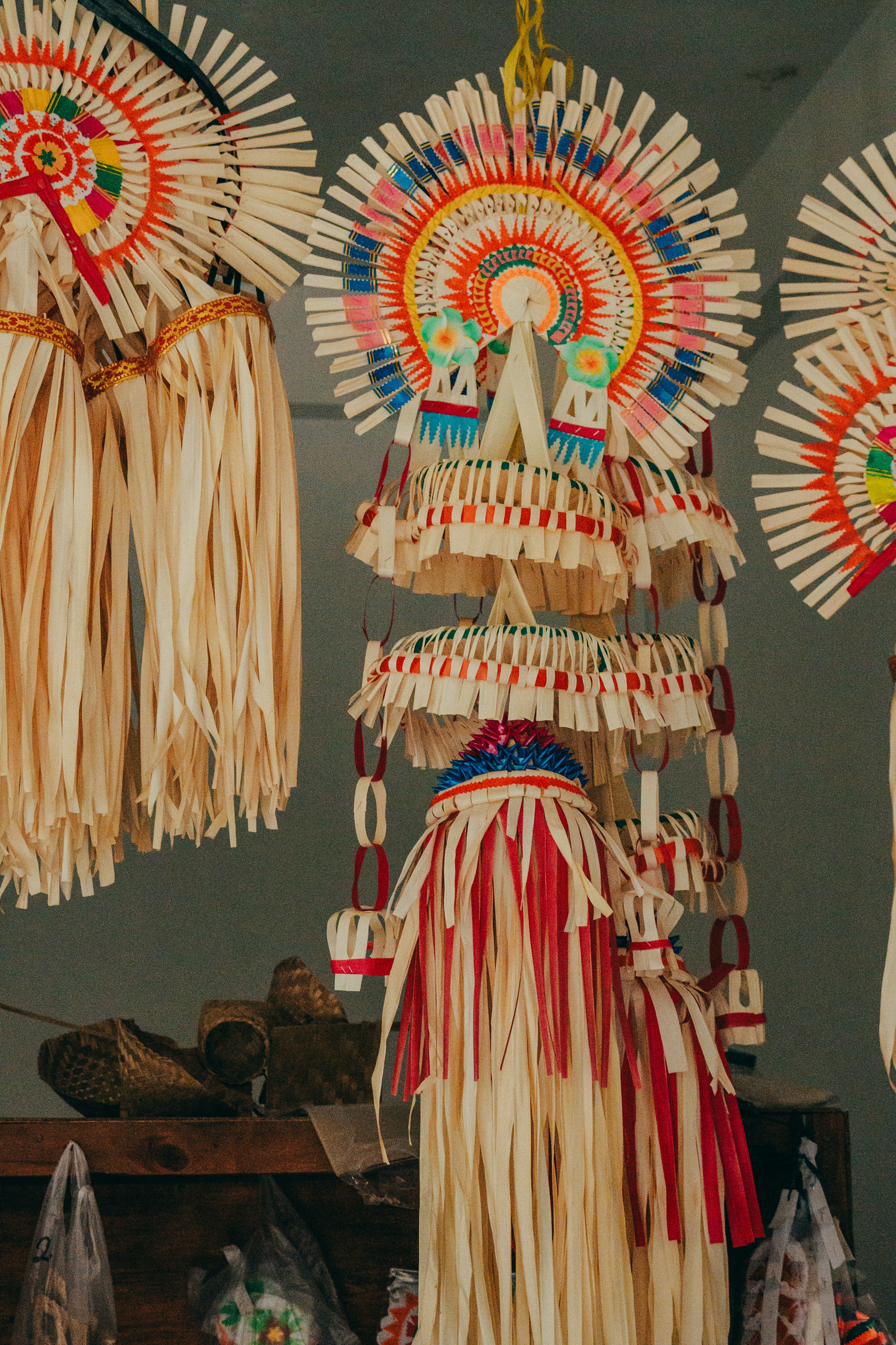 Colorful handmade decorations crafted from natural materials, showcasing intricate designs and cultural artistry. These woven pieces hang gracefully, reflecting craftsmanship and tradition.