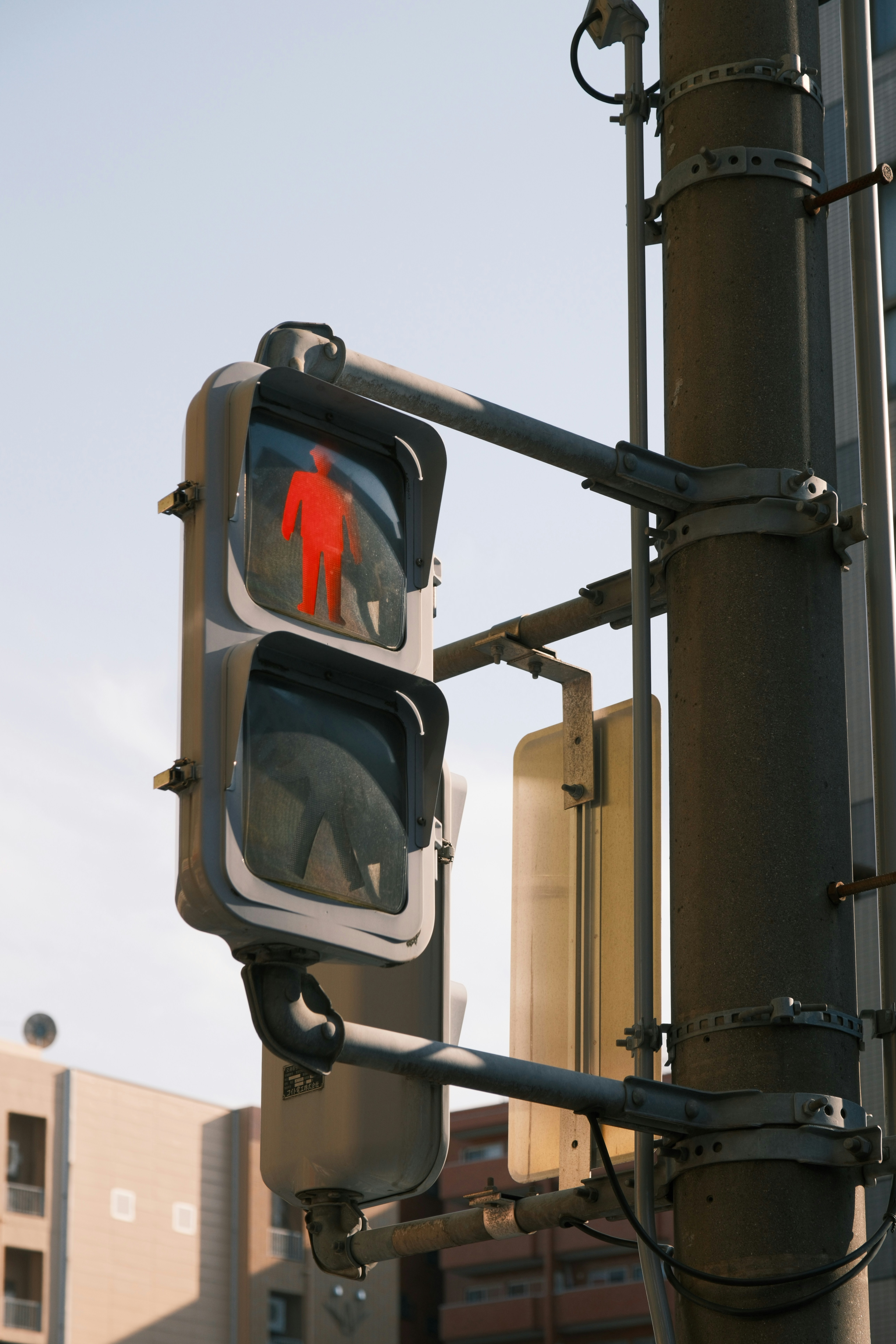 Crimson Pedestrian Signal Clings to Weathered Steel in Quiet Urban Light