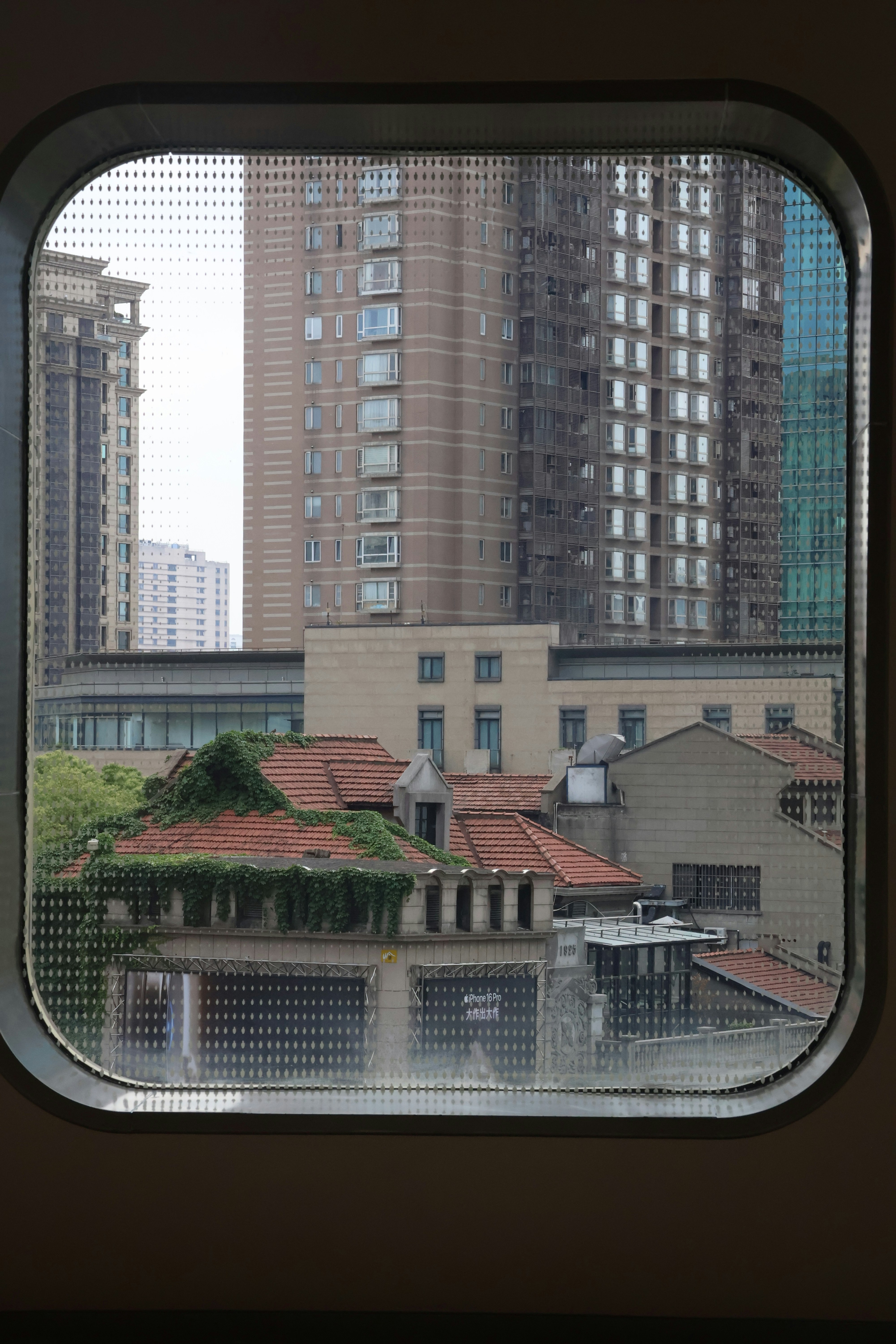 Looking out from a window on the third floor of Andaz Xintiandi Shanghai is a corner of the popular shopping district—Xintiandi with apartment buildings in the background | City buildings framed by a window.