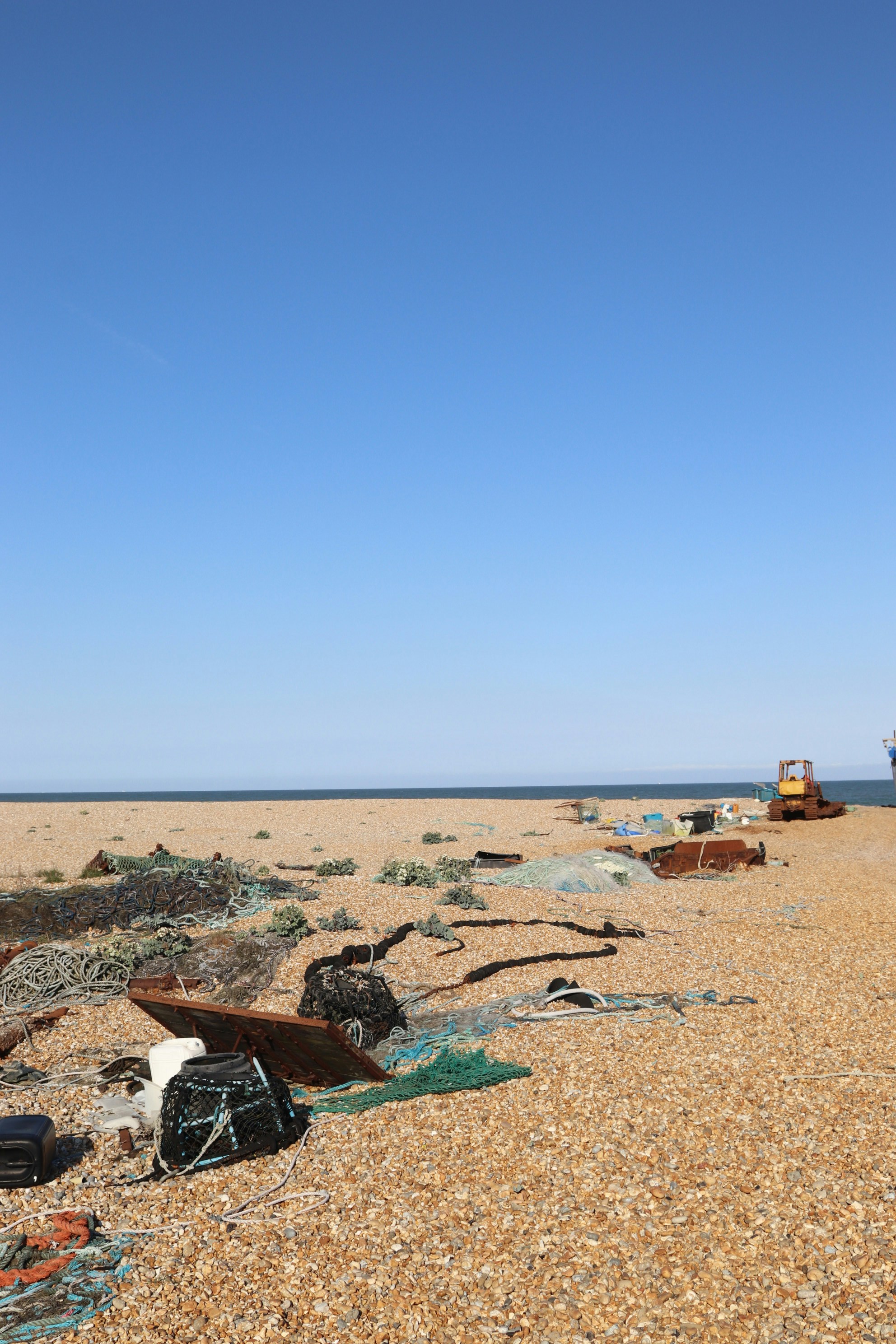 Edge of Tide: A Rusted Excavator Among Beach Debris on a Calm Horizon