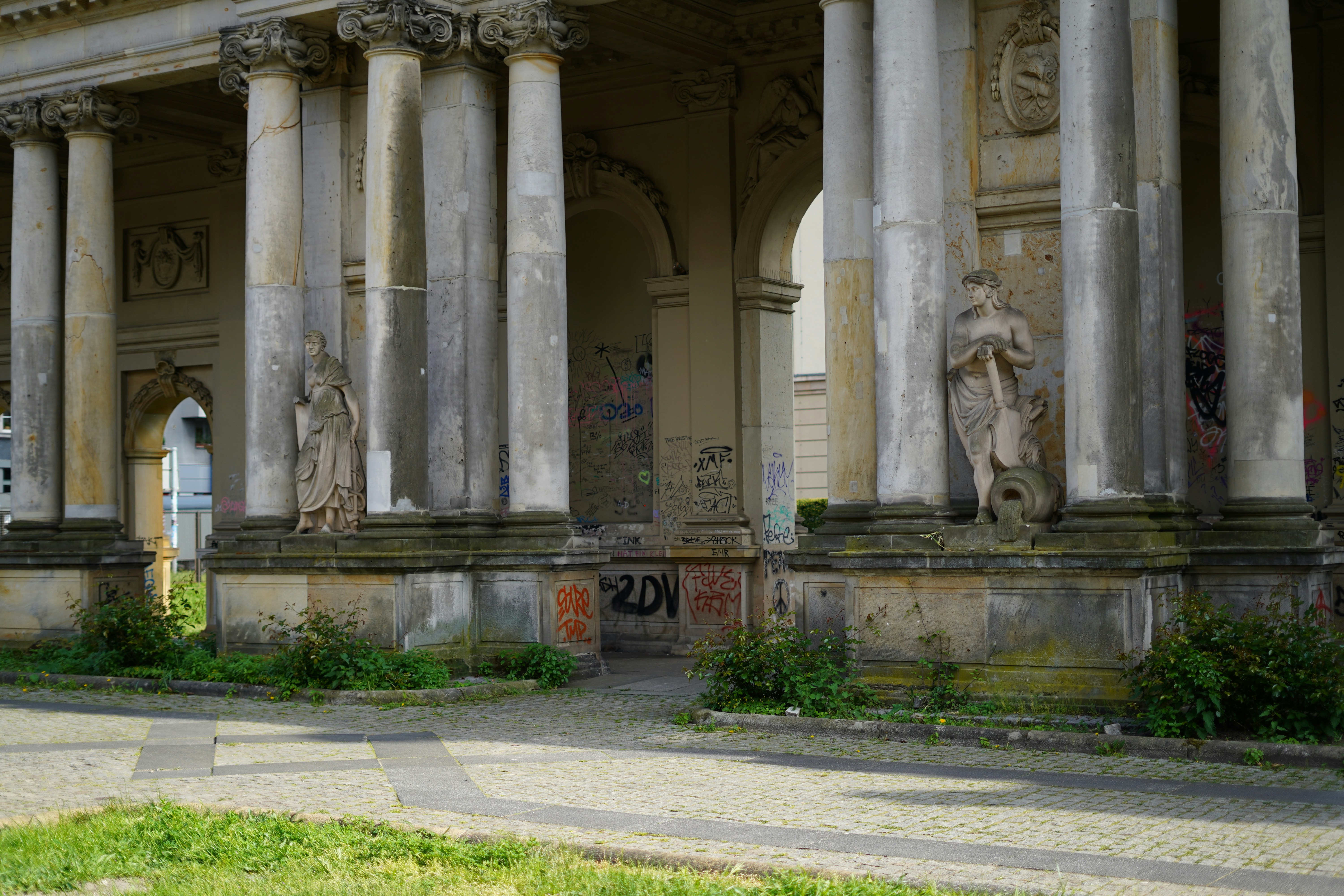 Timeworn Colonnade: Graffiti, Statues, and a Silent Archway