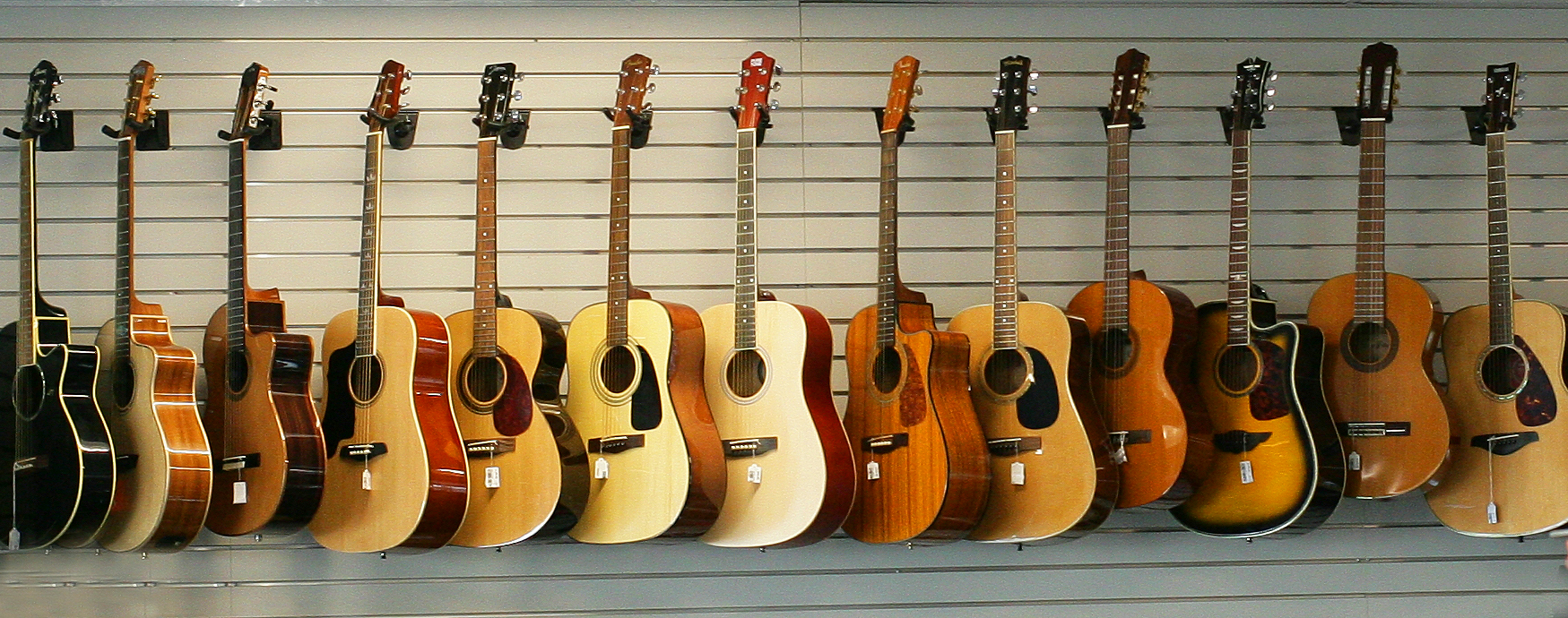 A variety of acoustic guitars are displayed on the wall.