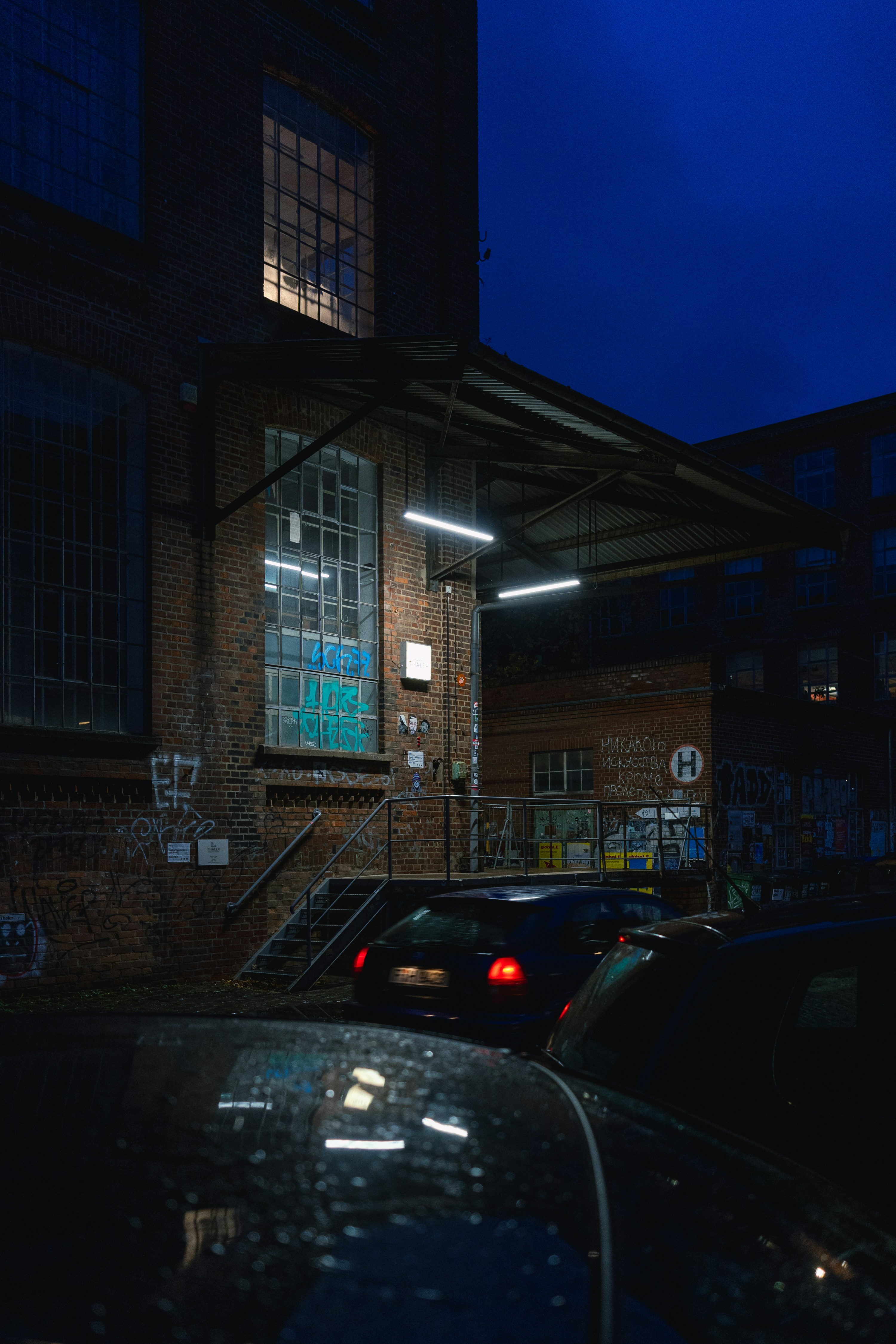 Dark, industrial building with cars parked out front. photo – Free ...