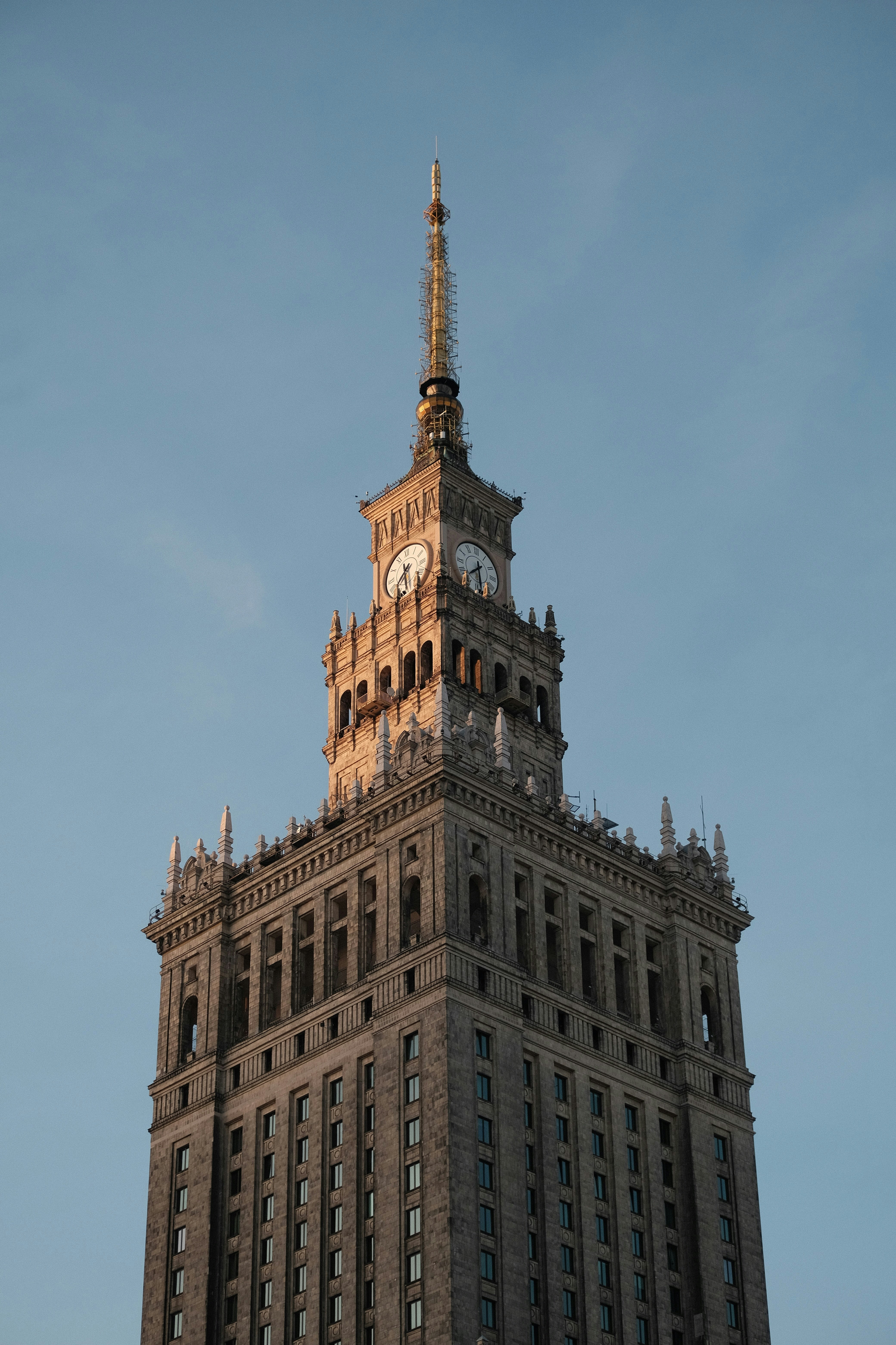 Historic skyscraper with intricate details and clock faces, reaching towards the sky against a serene backdrop.