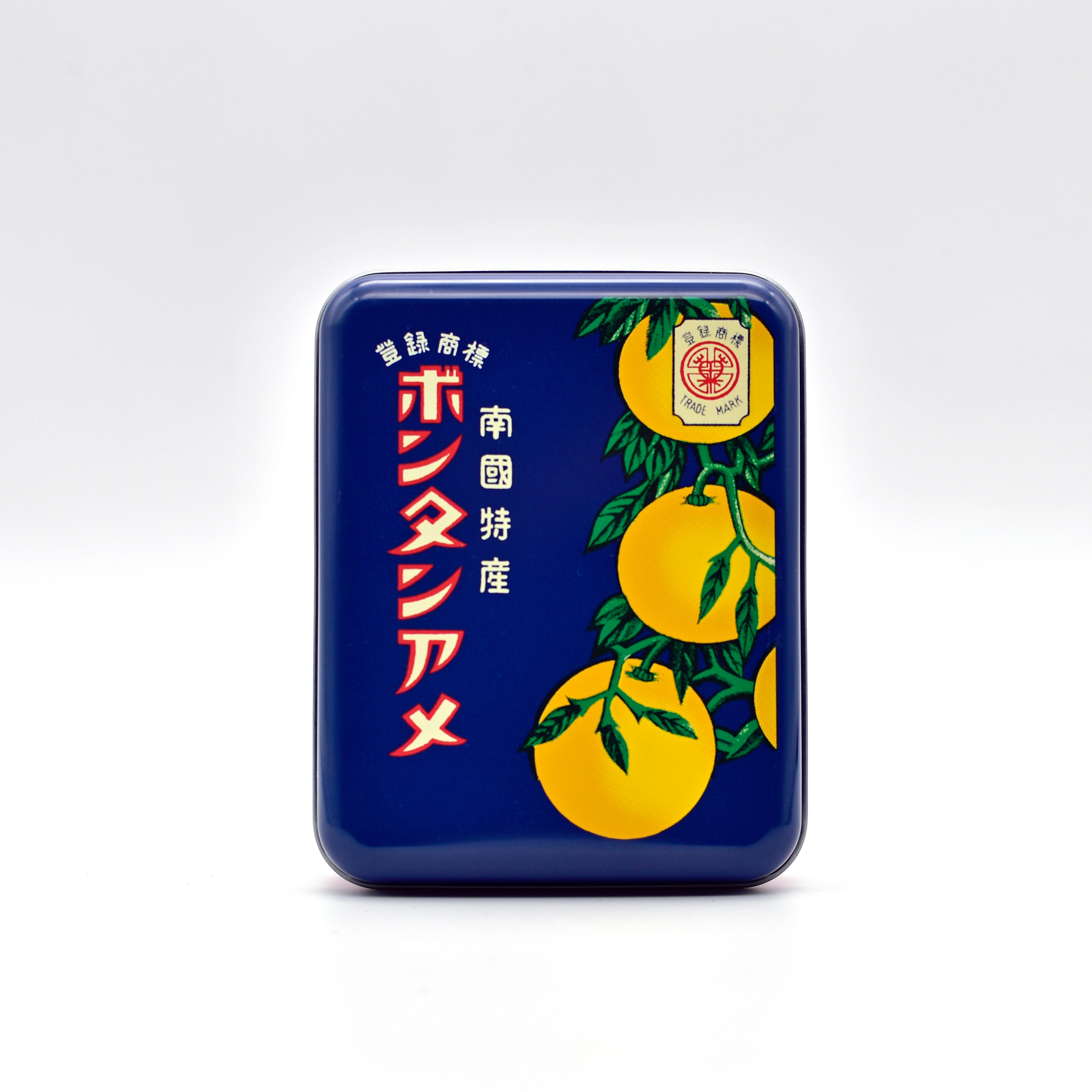 A vibrant blue tin featuring stylized orange fruits and Japanese text, showcasing traditional craftsmanship and branding. The design emphasizes the rich cultural heritage of the product.