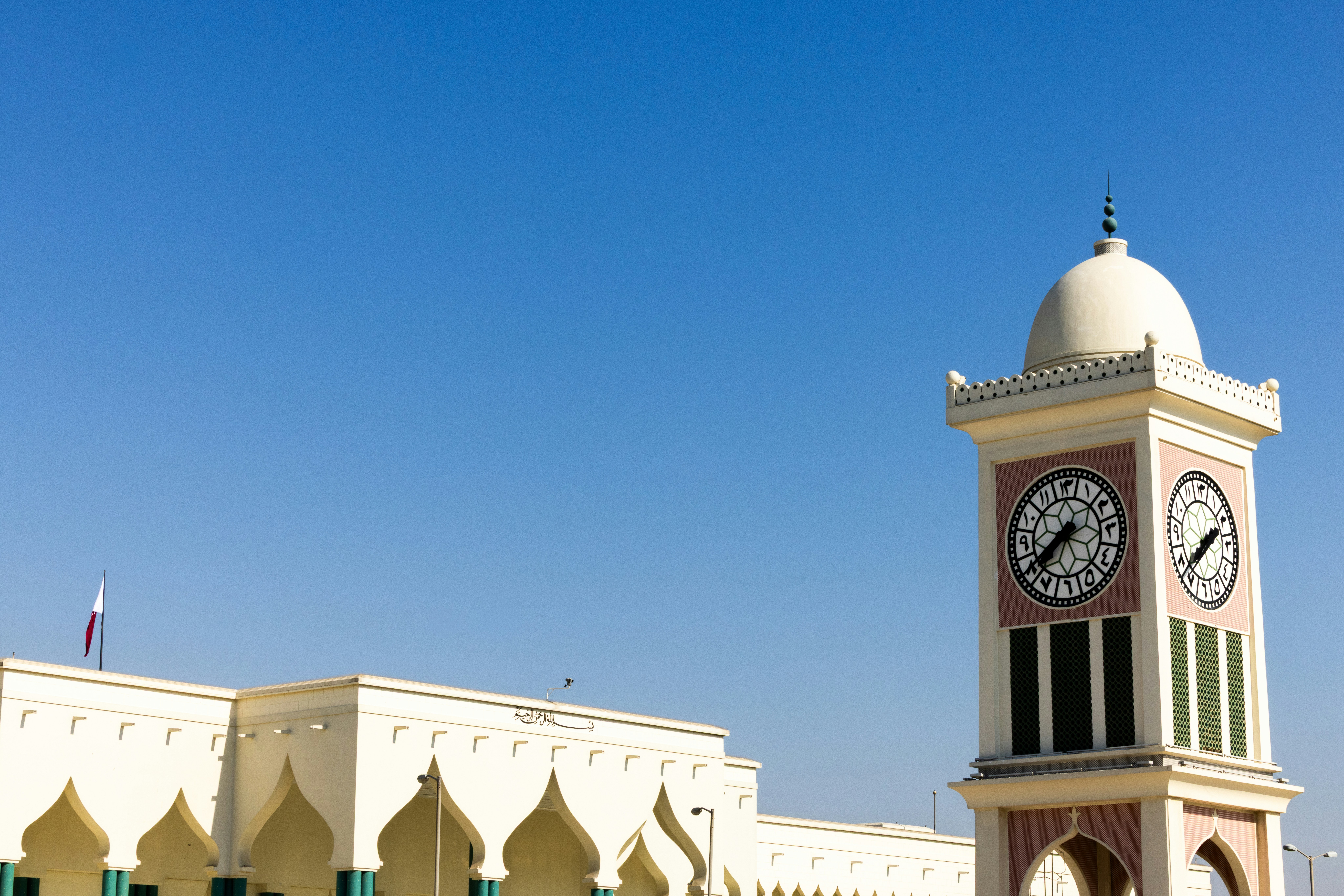 A historic clock tower stands proudly against a clear blue sky, showcasing architectural details and a vibrant color palette.