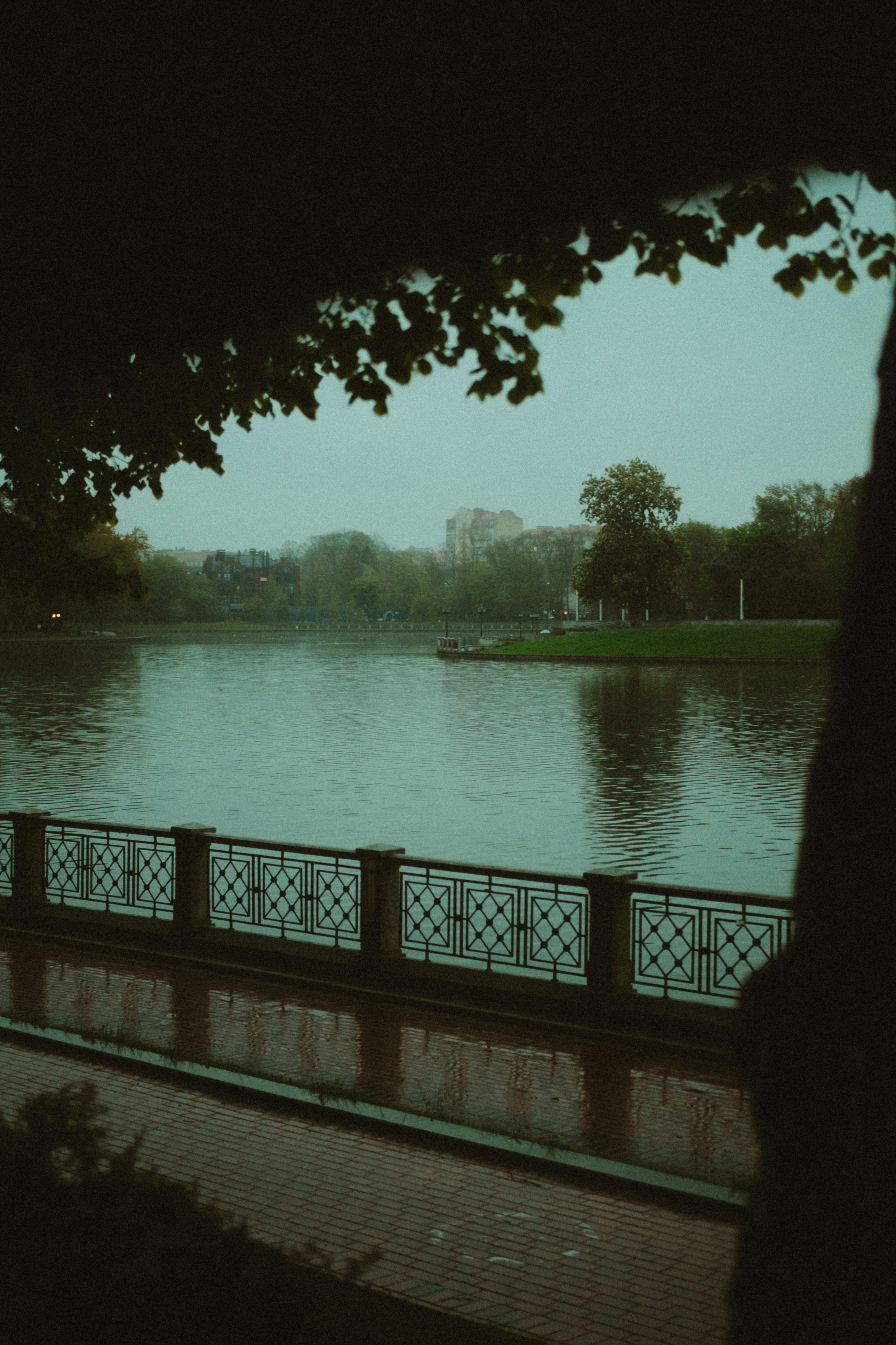 Quiet Riverside: Iron Railings, Calm Lake, and a Distant Skyline
