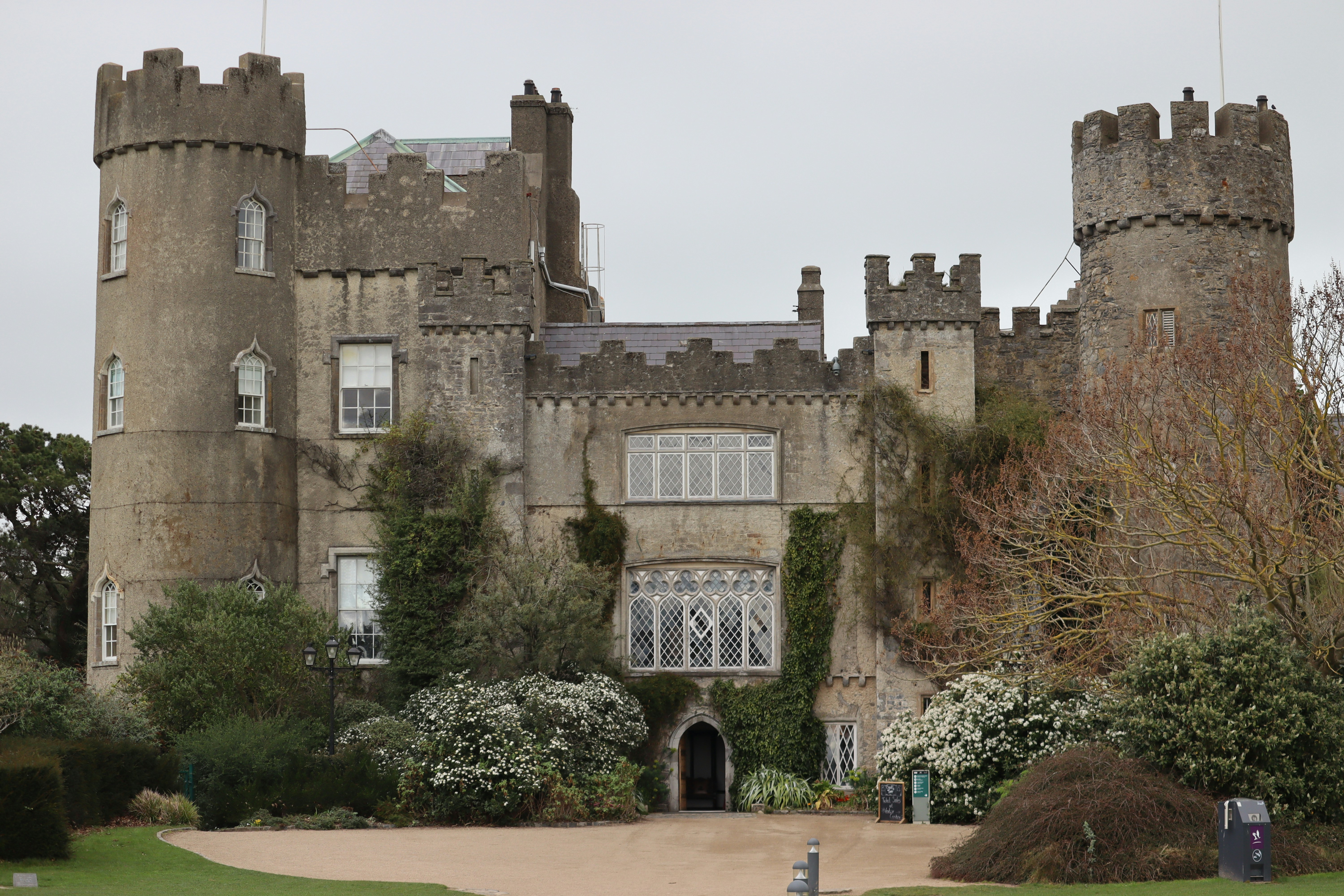 A large castle stands in the middle of lush greenery.