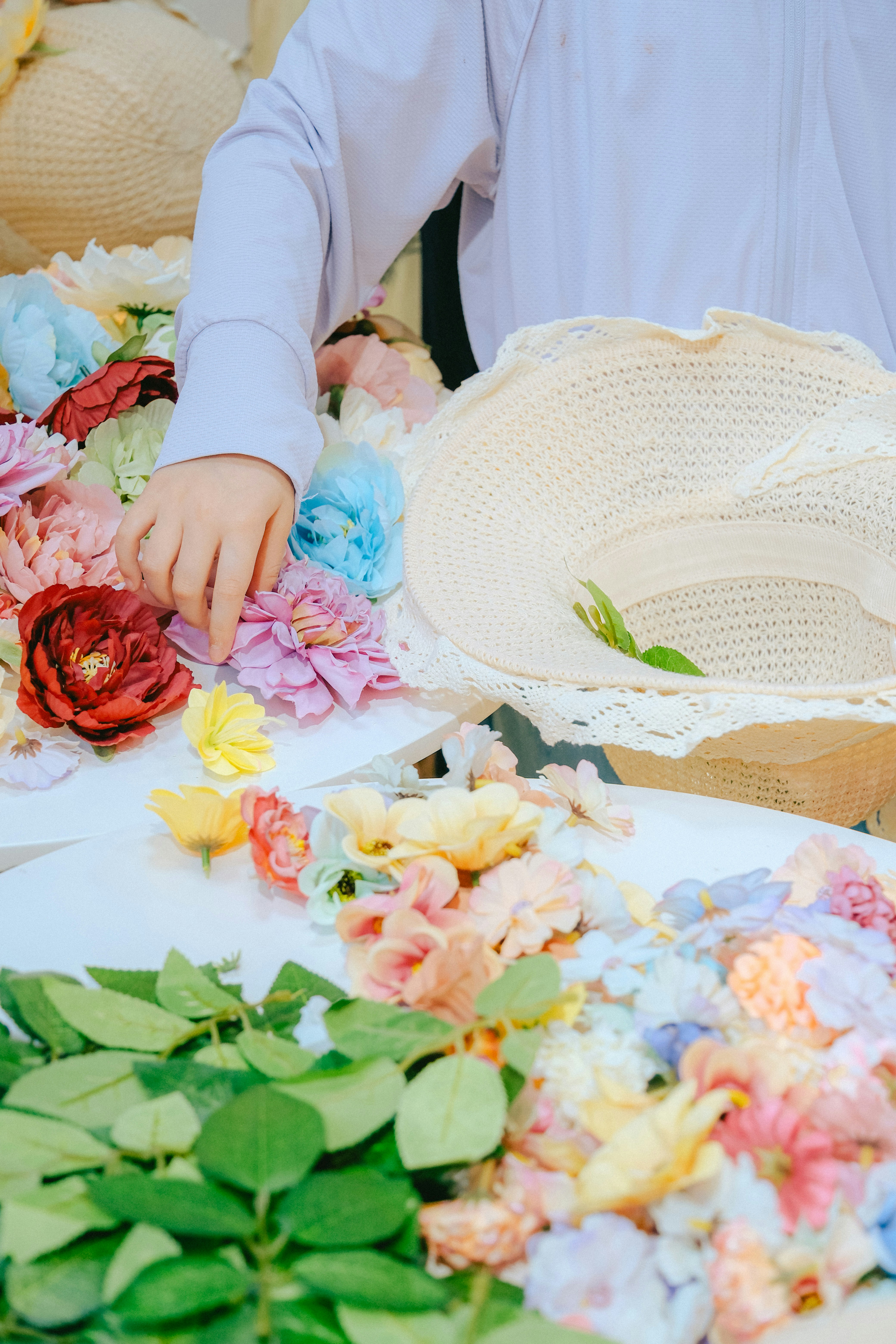Pastel Hand Among a Table of Spring Blooms and a Crochet Hat