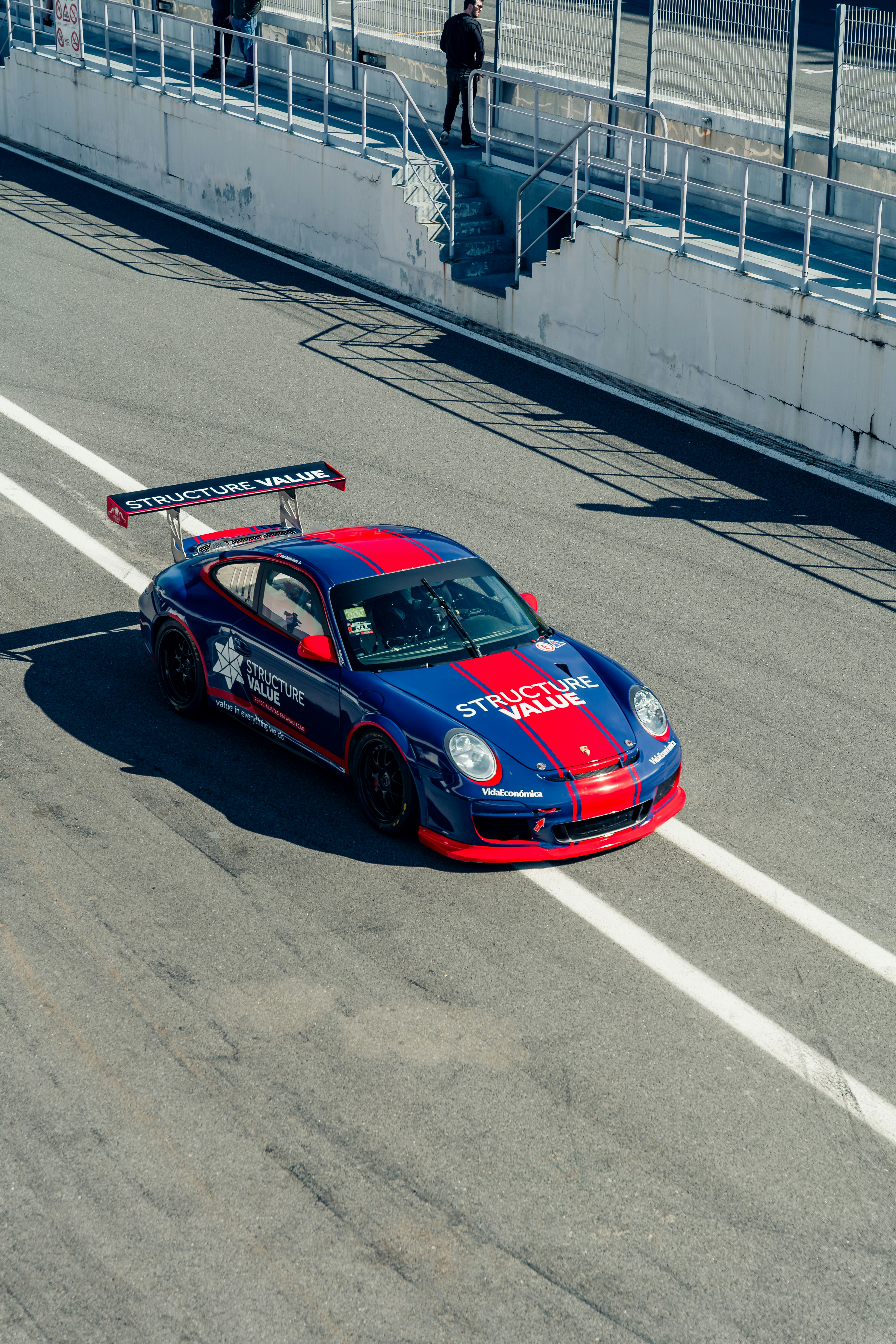 A blue and red race car speeds on a track. photo – Free Porsche Image ...