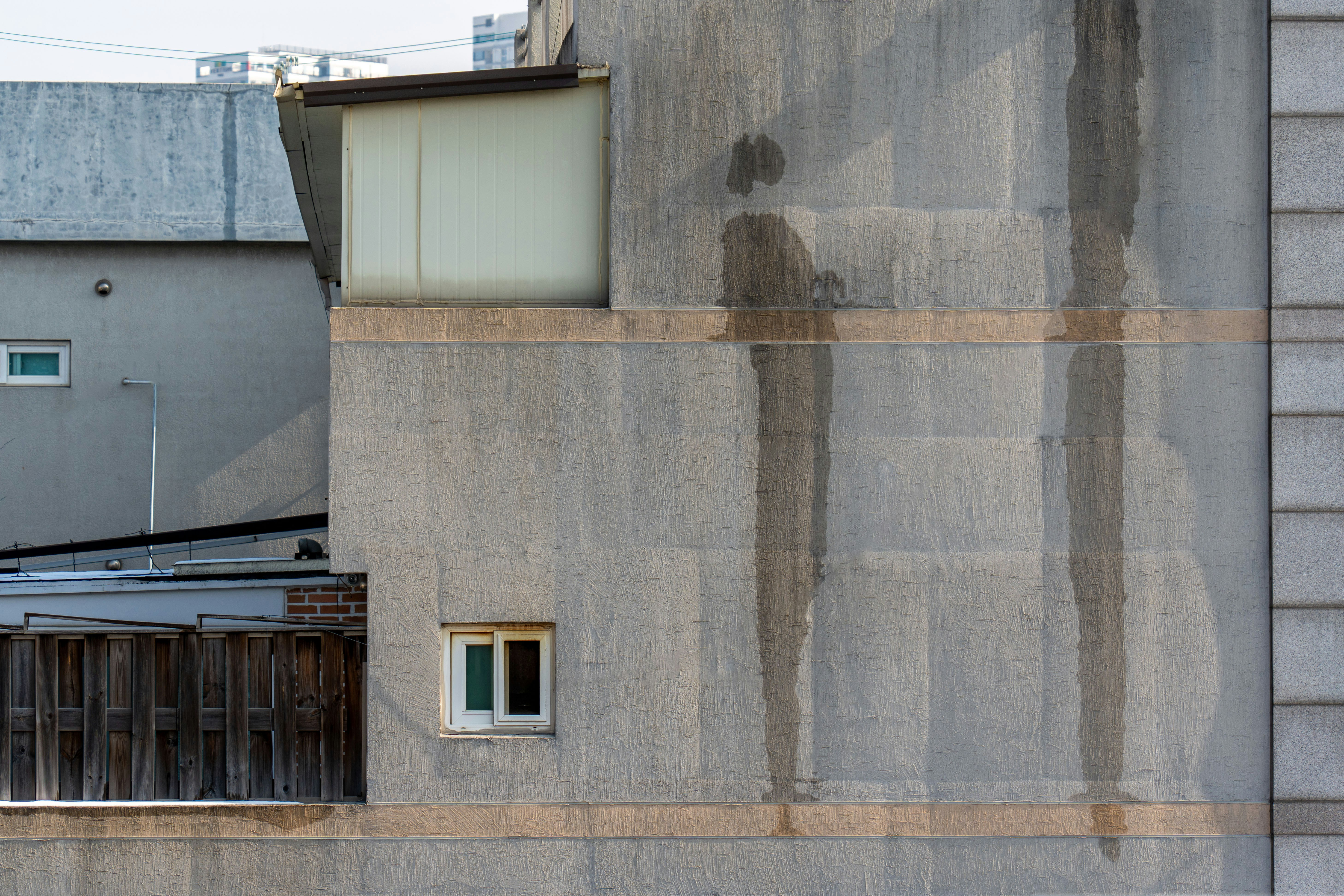Quiet Geometry on a Weathered City Wall: A Small Window Amid Streaked Concrete