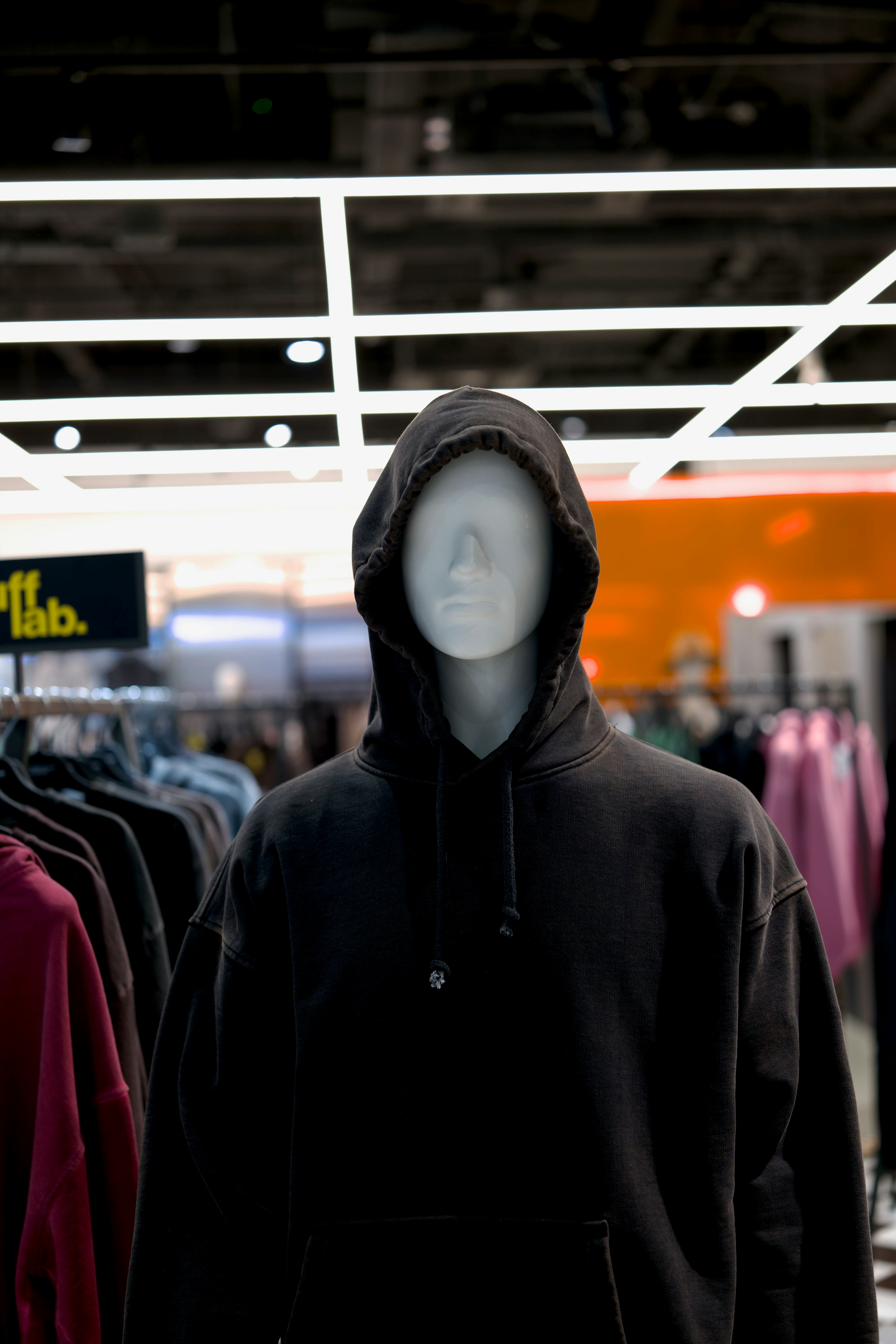 Hooded Sentinel Between Neon Racks