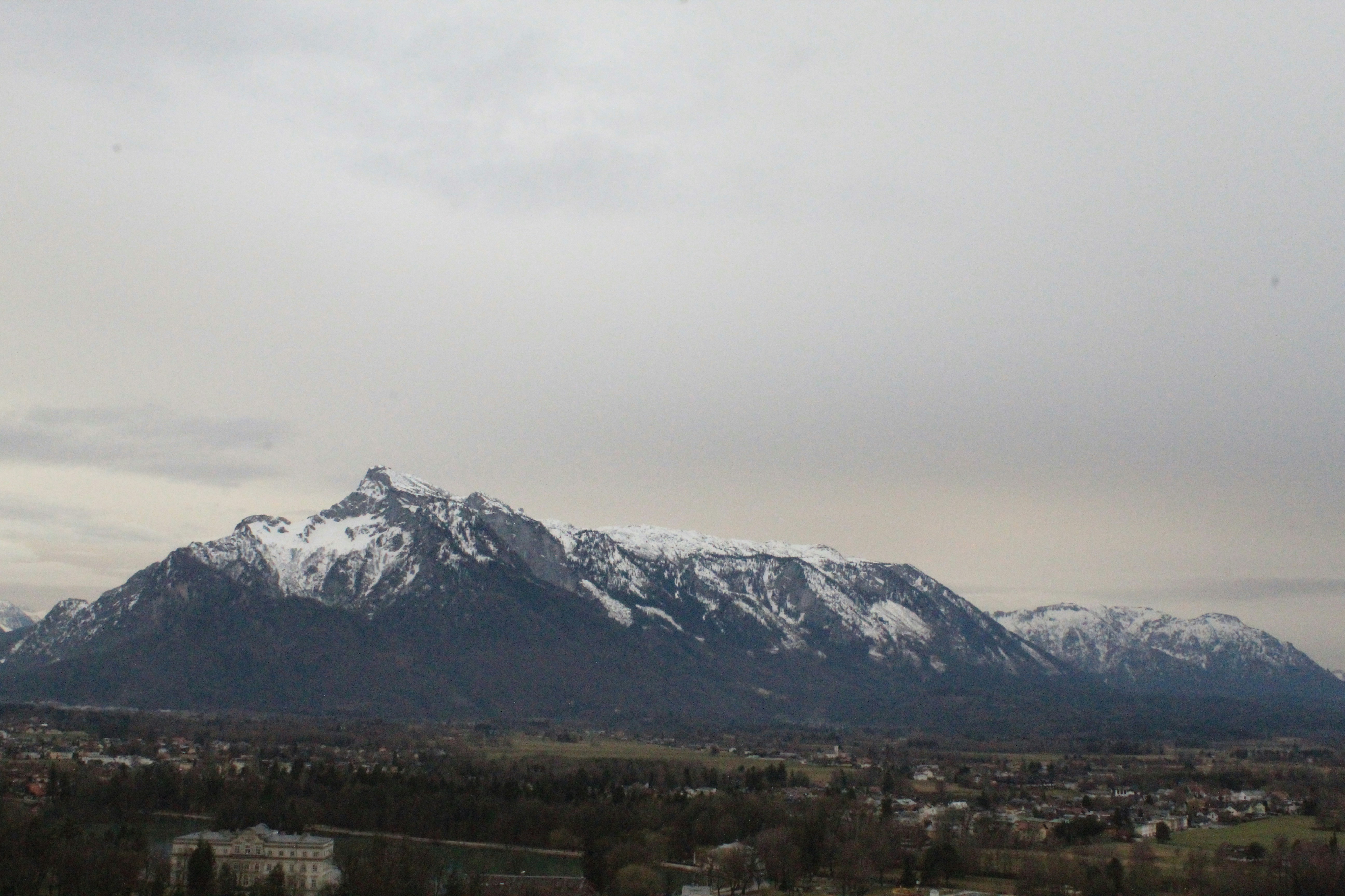Snow-capped mountains loom under a cloudy sky.