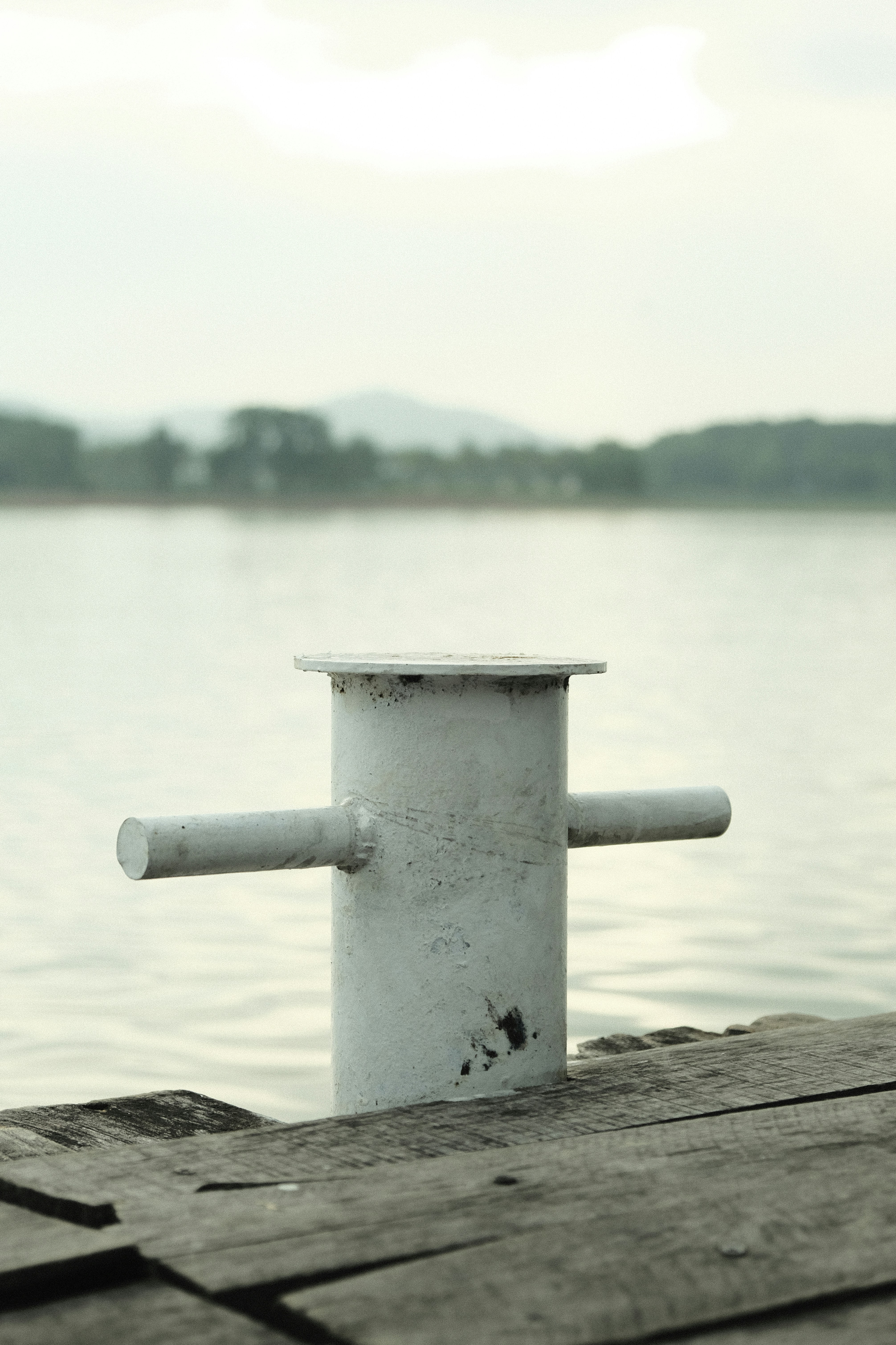 Mooring Silence: A Weathered Bollard Framing a Lake's Quiet Horizon