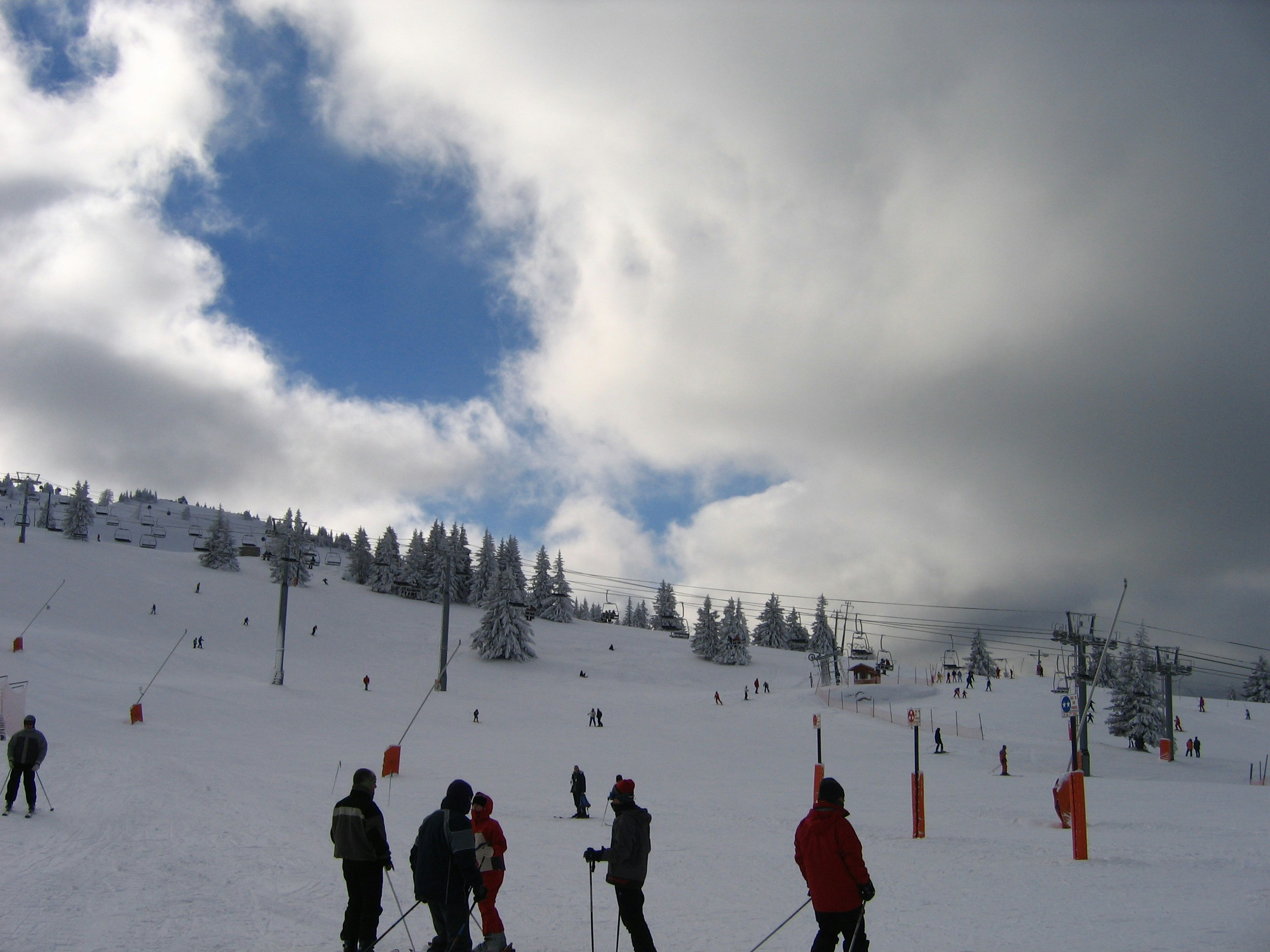 Skiers enjoy a snowy mountain on a cloudy day.