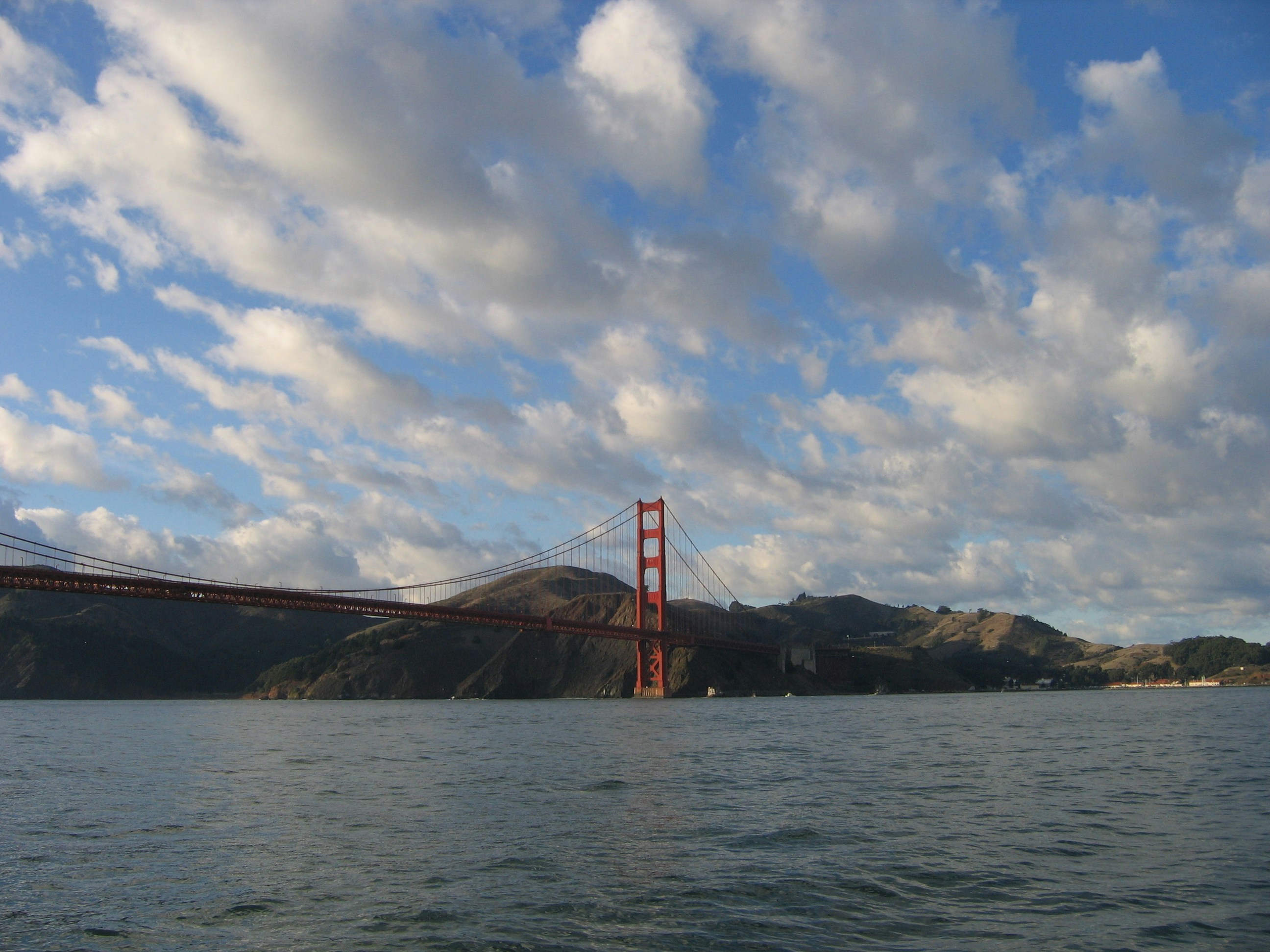 Golden Gate Bridge towering over calm waters with dramatic cloud formations in the background.