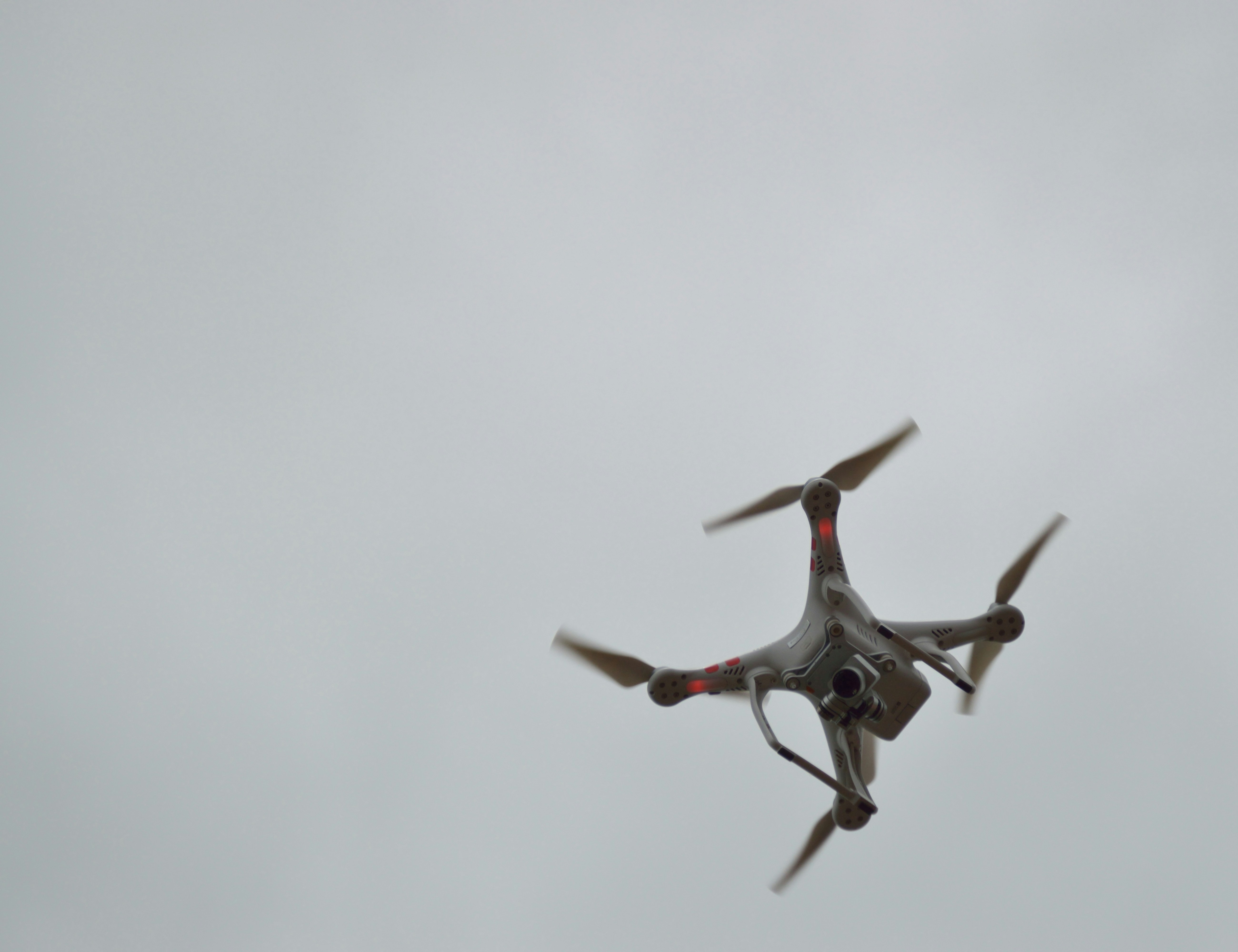 A quadcopter drone hovers against a gray sky, showcasing its intricate design and technology.