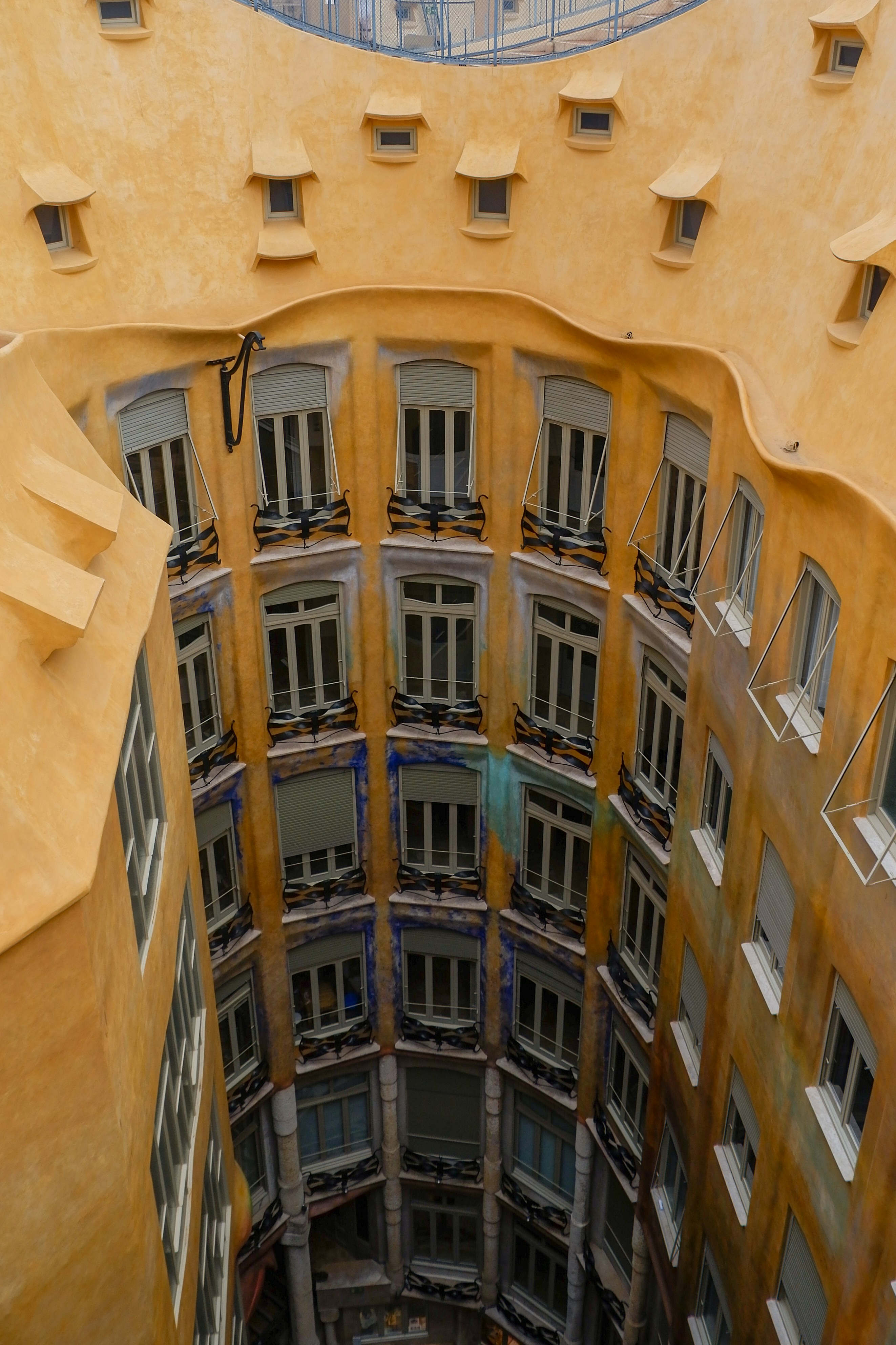 Interior view of a unique architectural space with curved walls, showcasing a blend of light and shadow through multiple windows.