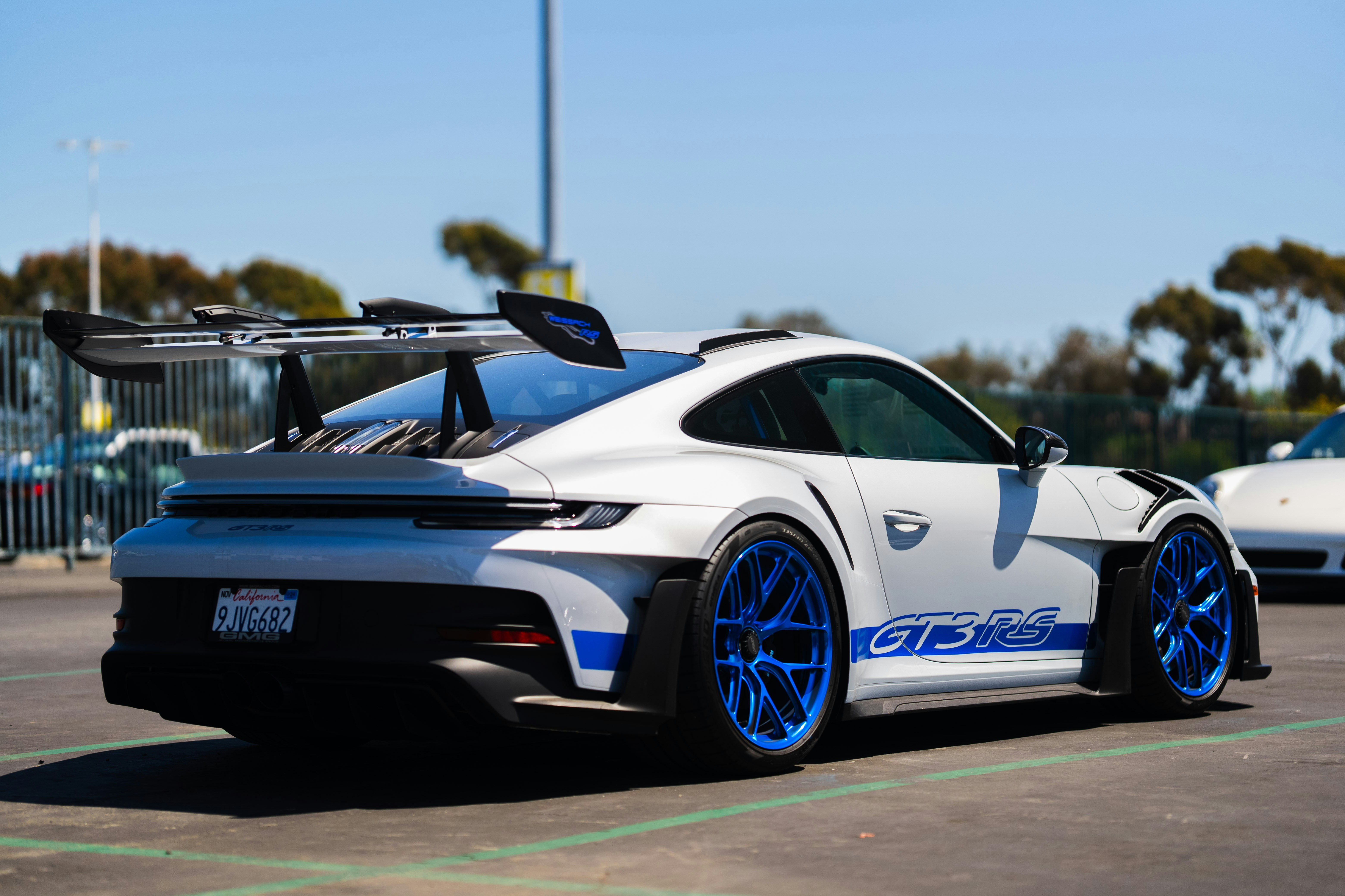 Electric-Blue Wheels on a White GT3 RS Under a Sunlit Sky