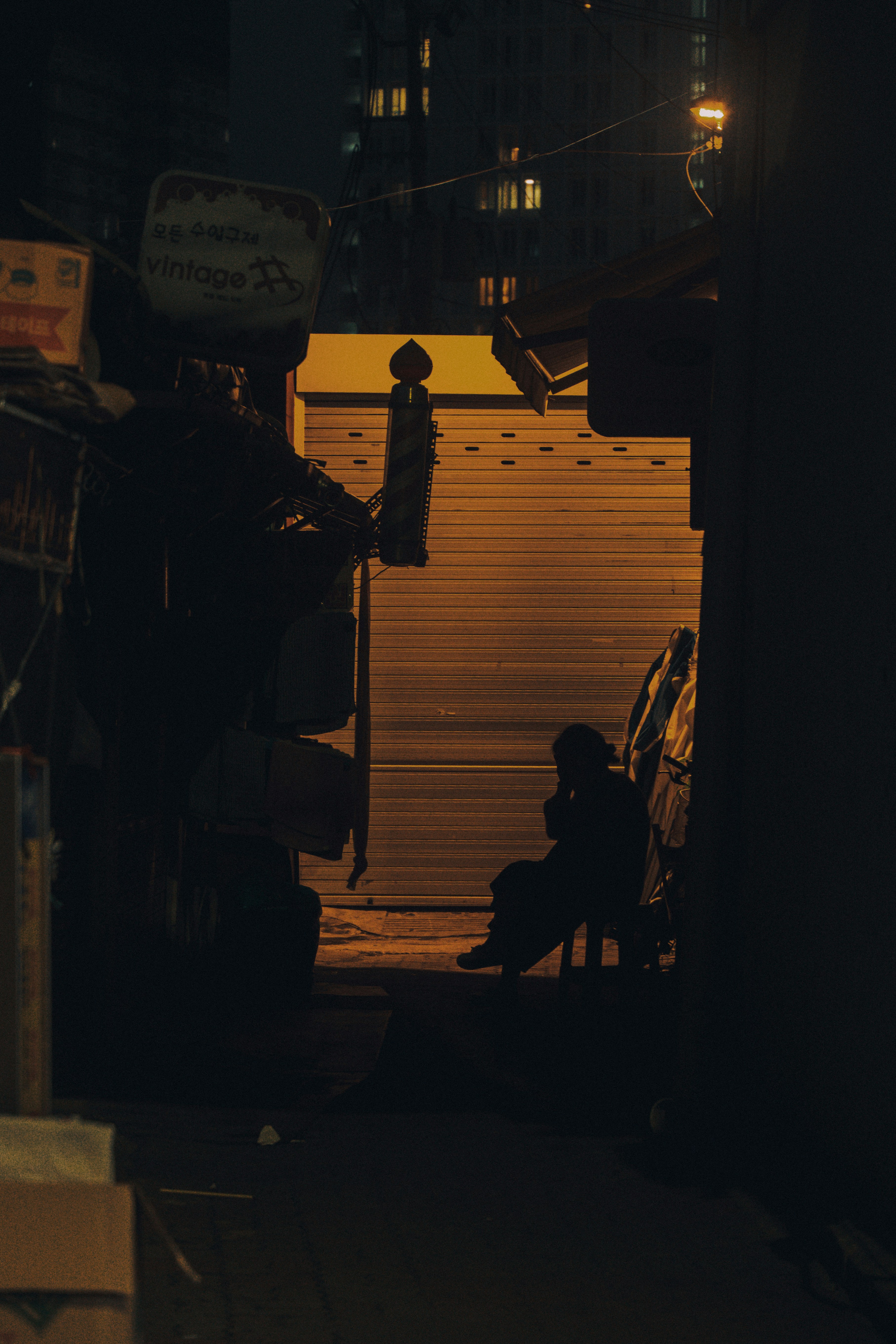 A silhouette sits in a dim, lit alley. photo – Free Image on Unsplash