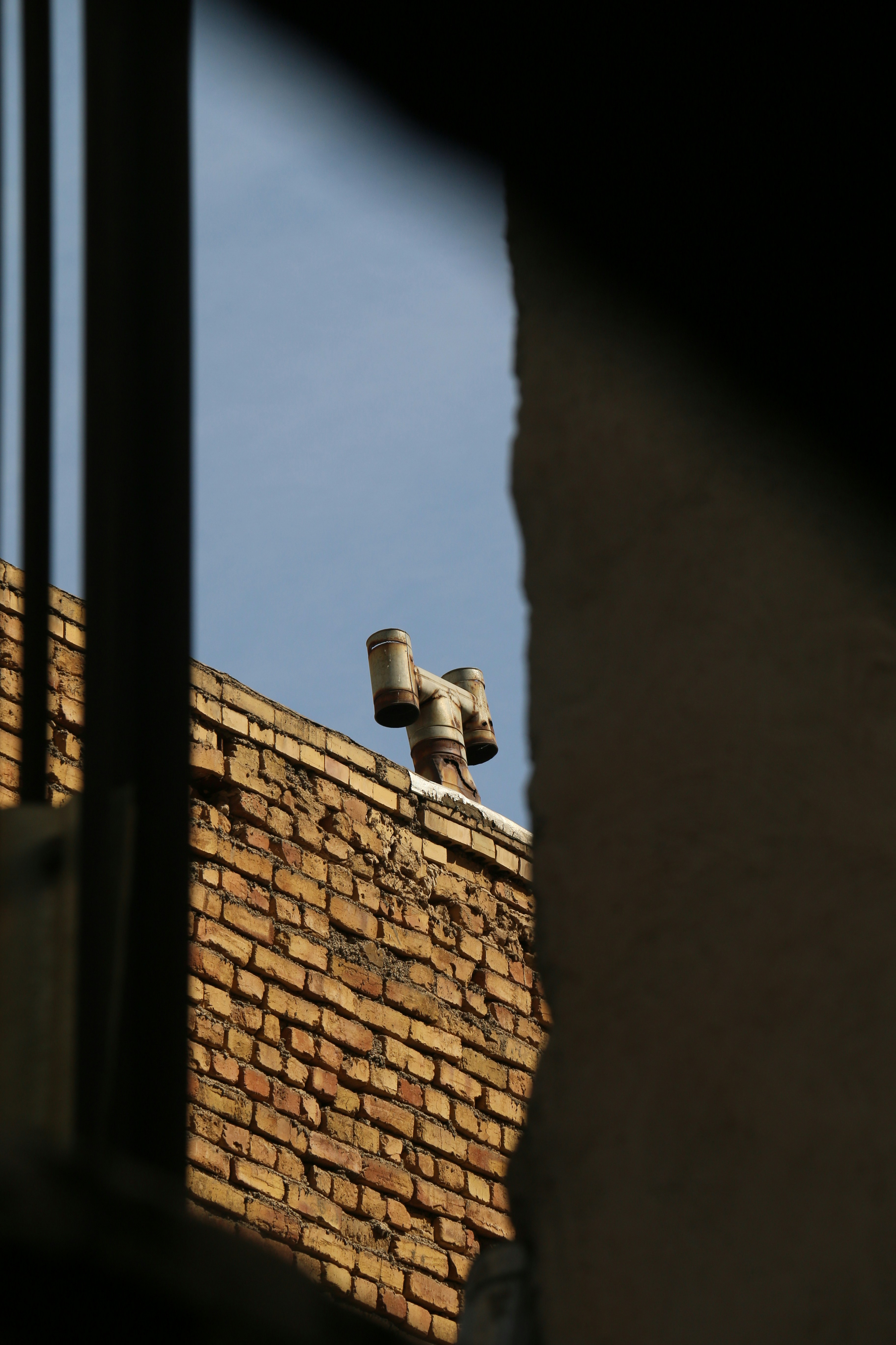 Rooftop Vent on Brick Wall Framed by a Shadowed Opening